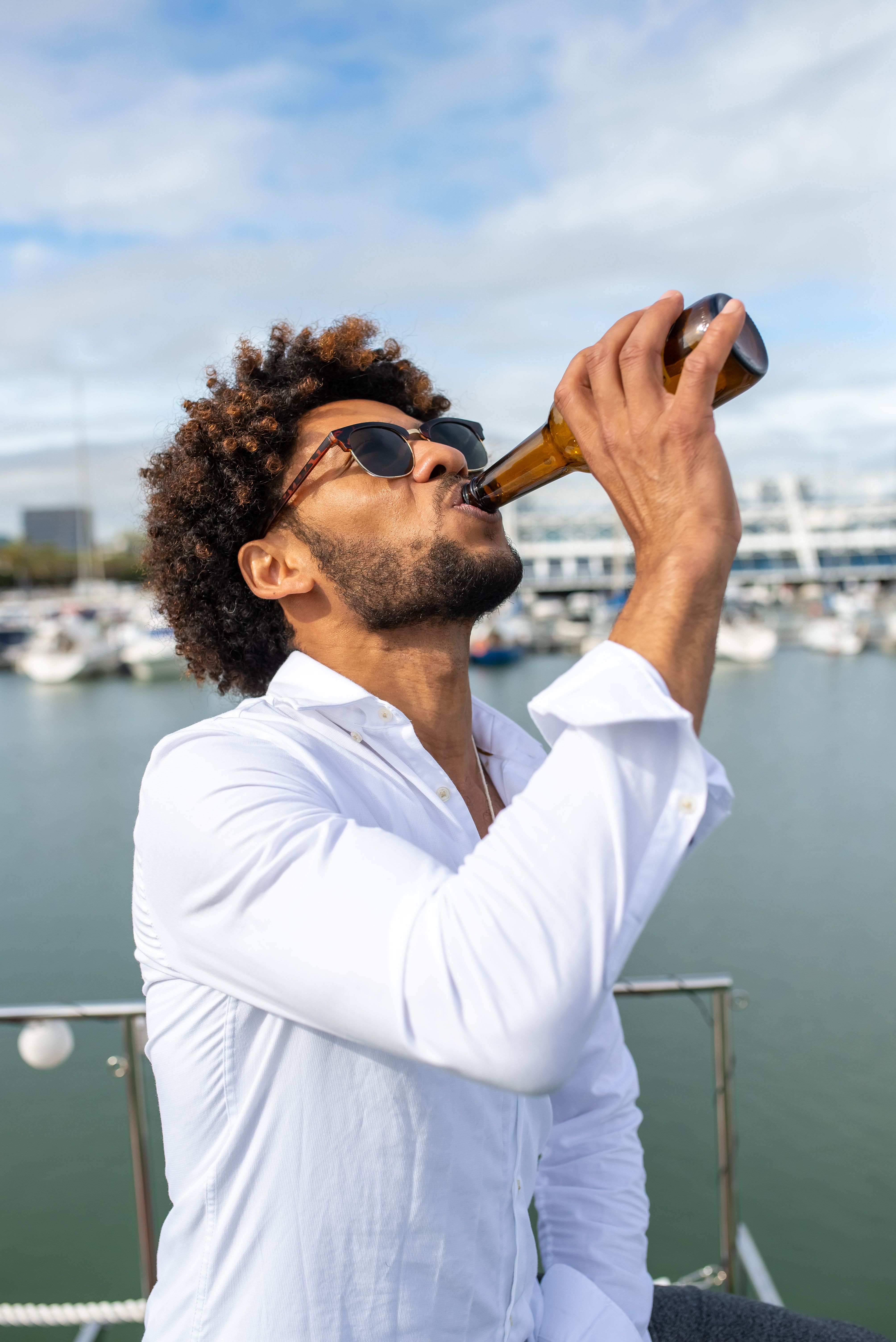 Man Drinking from Bottle on Yacht in Bay · Free Stock Photo