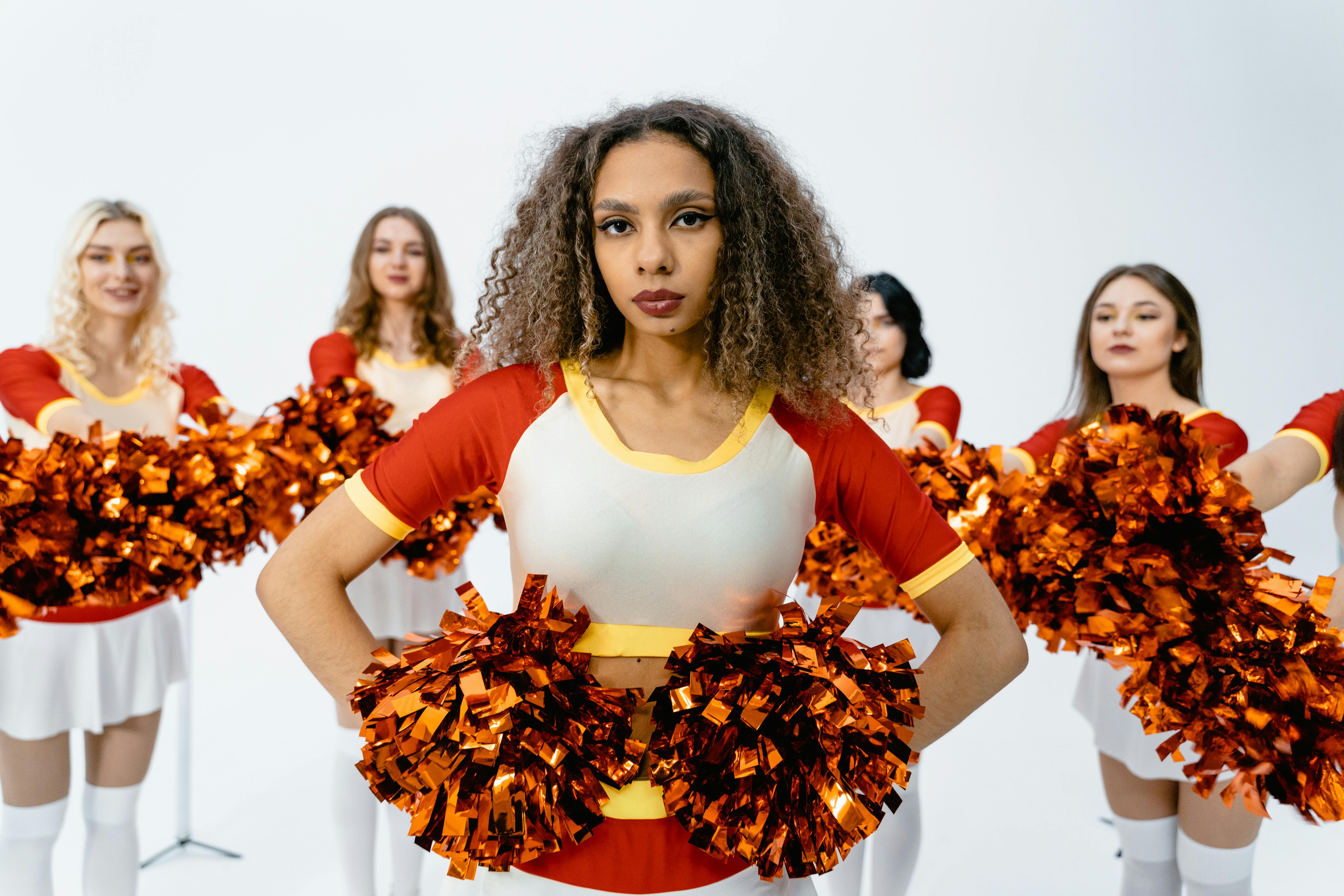 A Cheerleader with Curly Hair Leading a Squad · Free Stock Photo