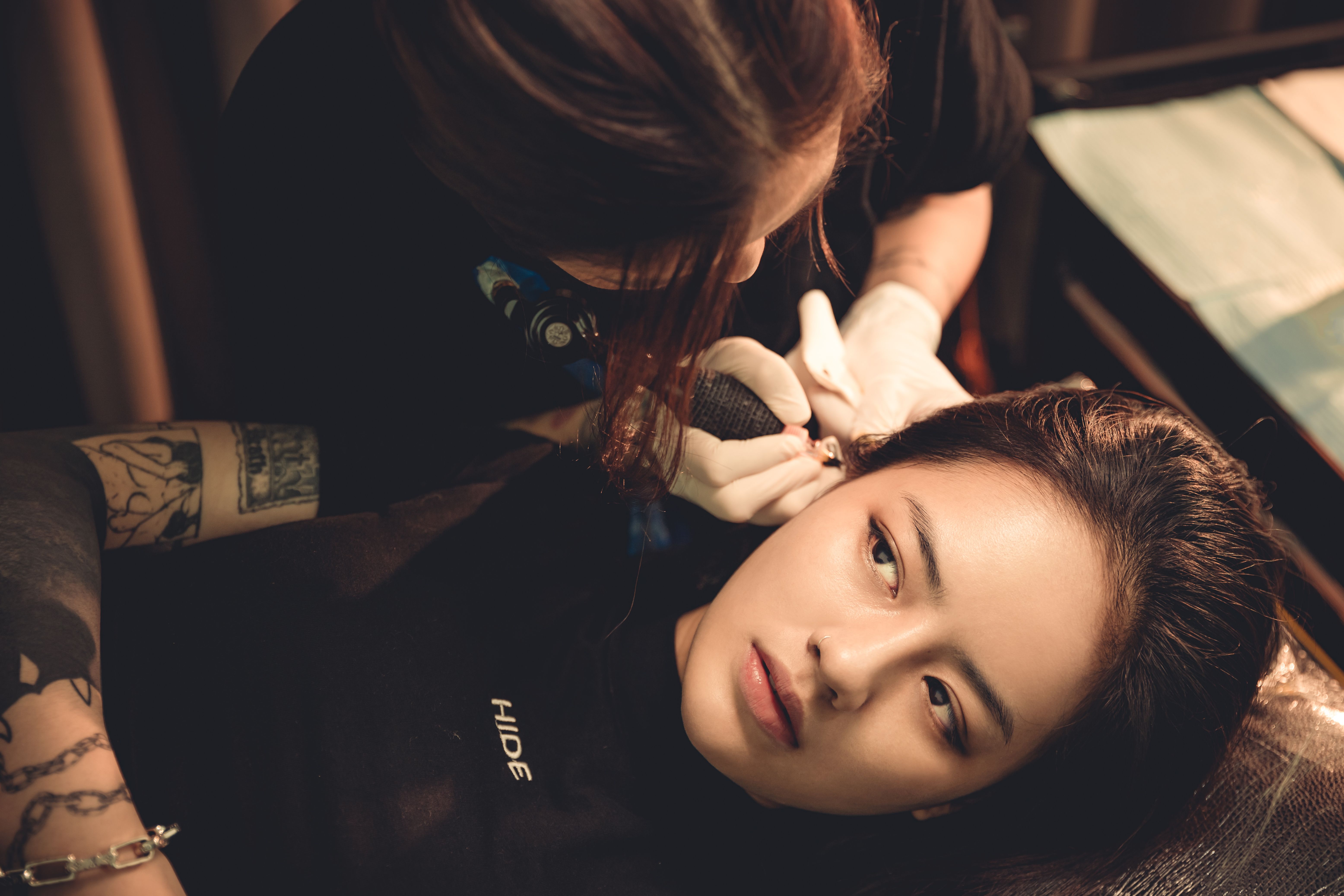 A Woman with Black Gloves Tattooing Another Person · Free Stock Photo