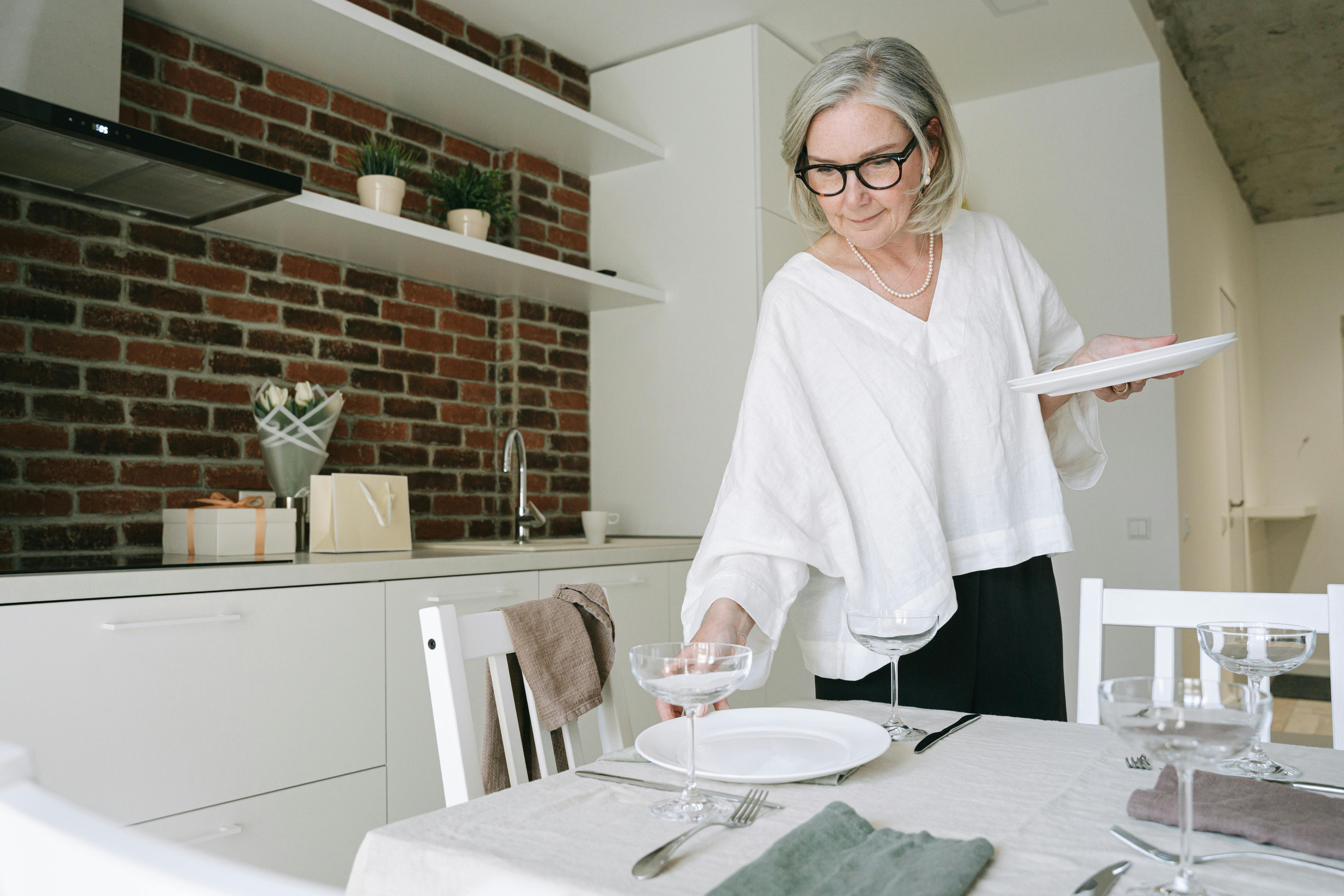 Elderly Woman in White Blouse Setting the Table · Free Stock Photo