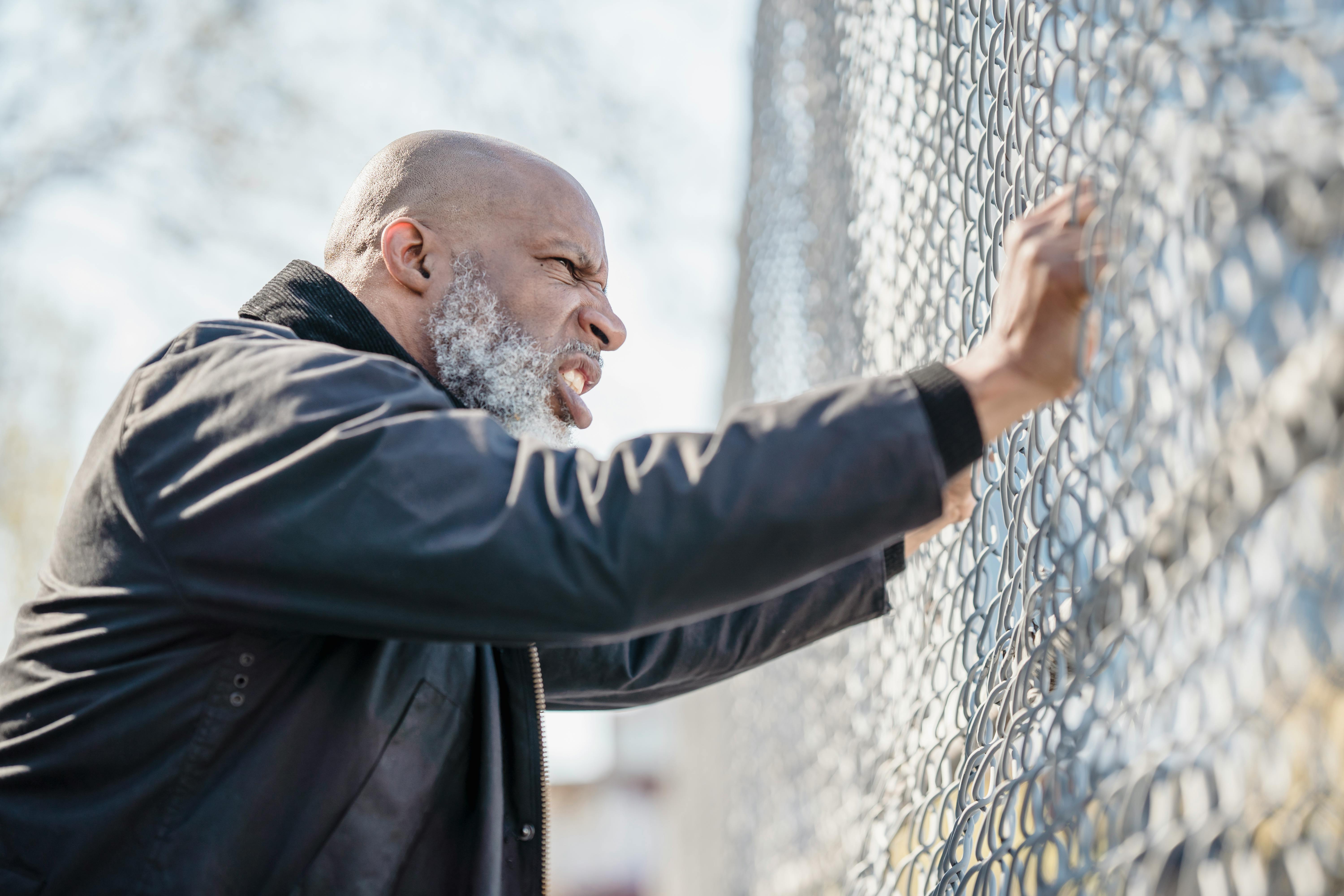 Angry Man Grasping Fence Net · Free Stock Photo