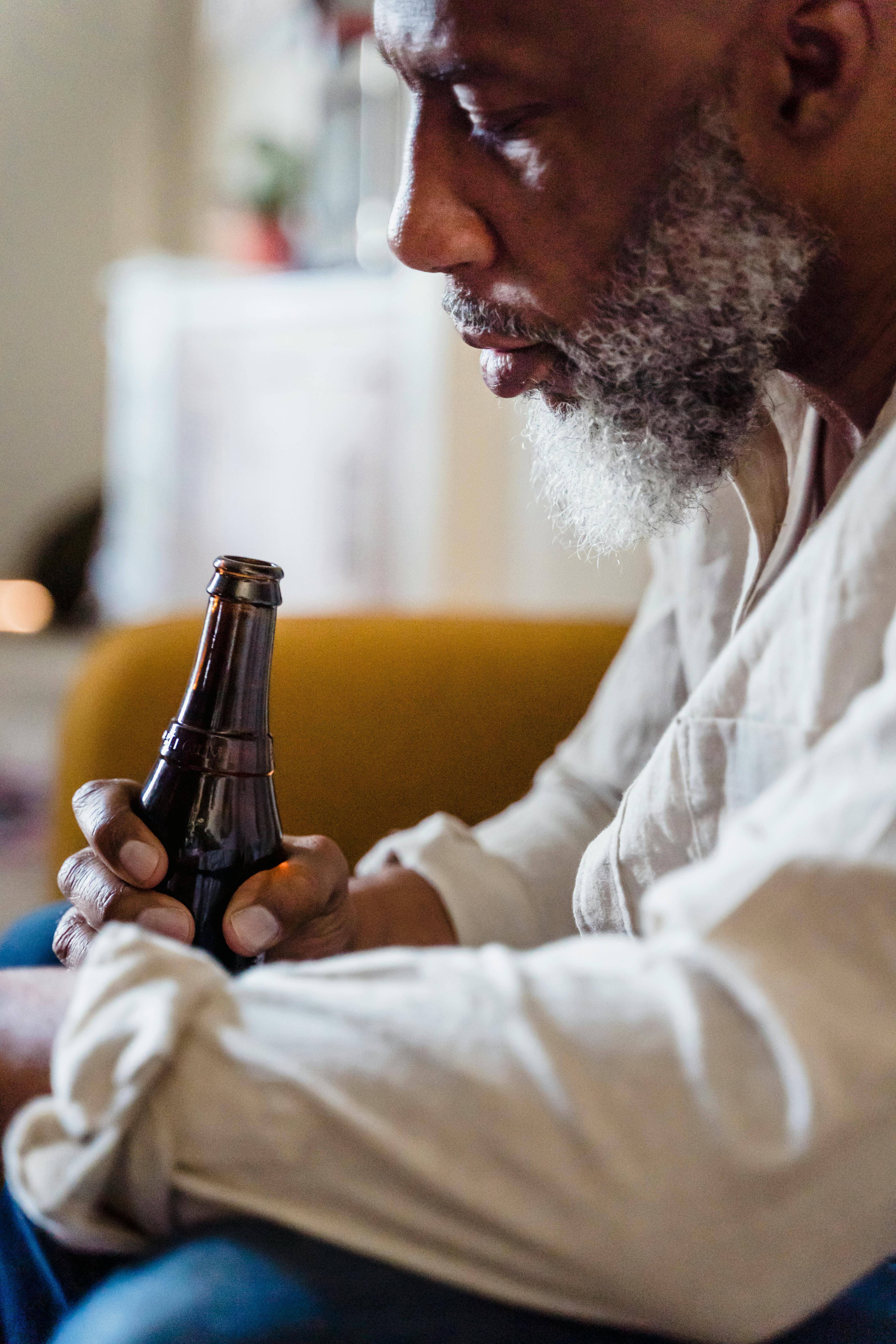 Sad Man Drinking a Bottle of Beer on a Couch · Free Stock Photo