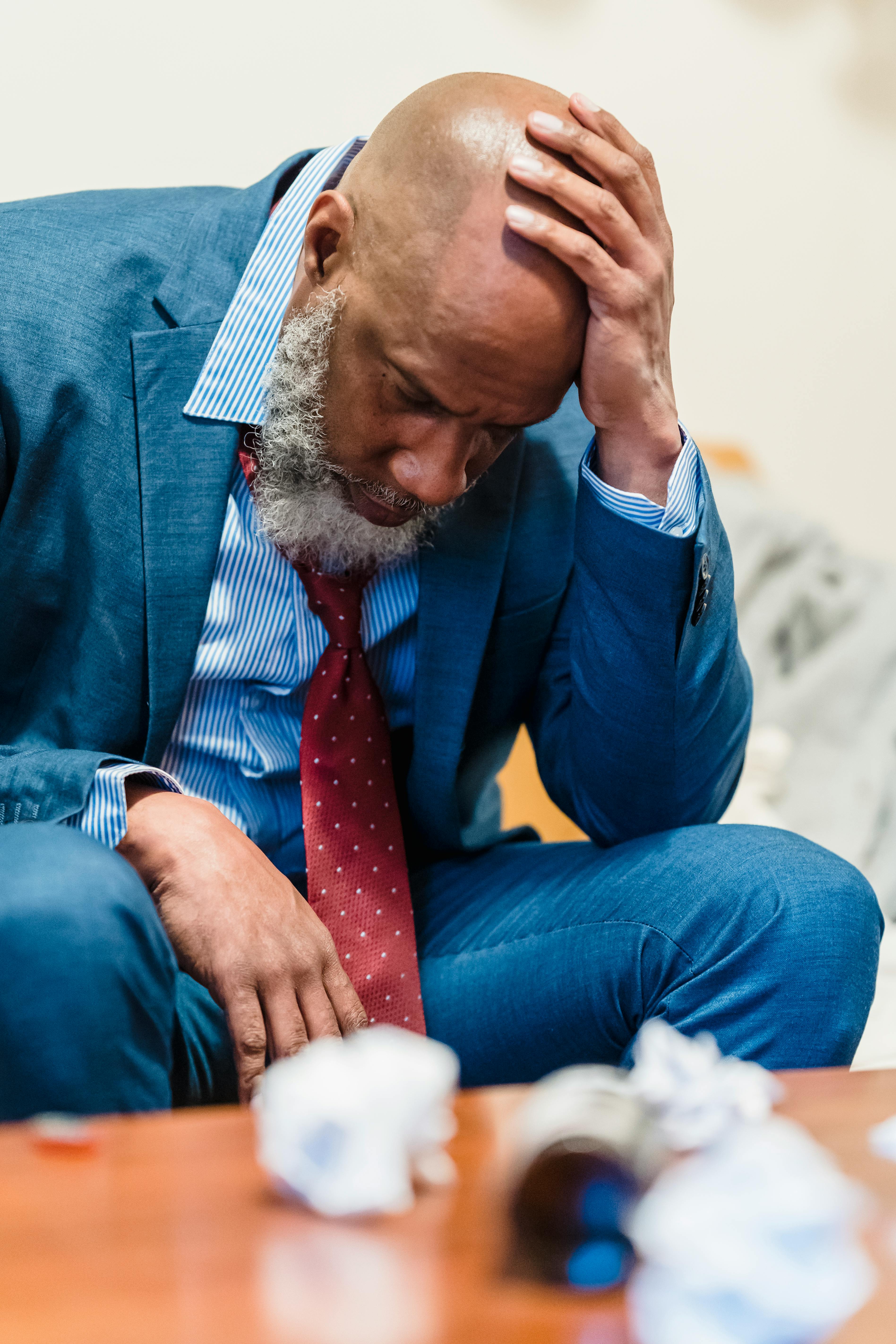 Stressed Man on Blue Suit Sitting on Sofa · Free Stock Photo