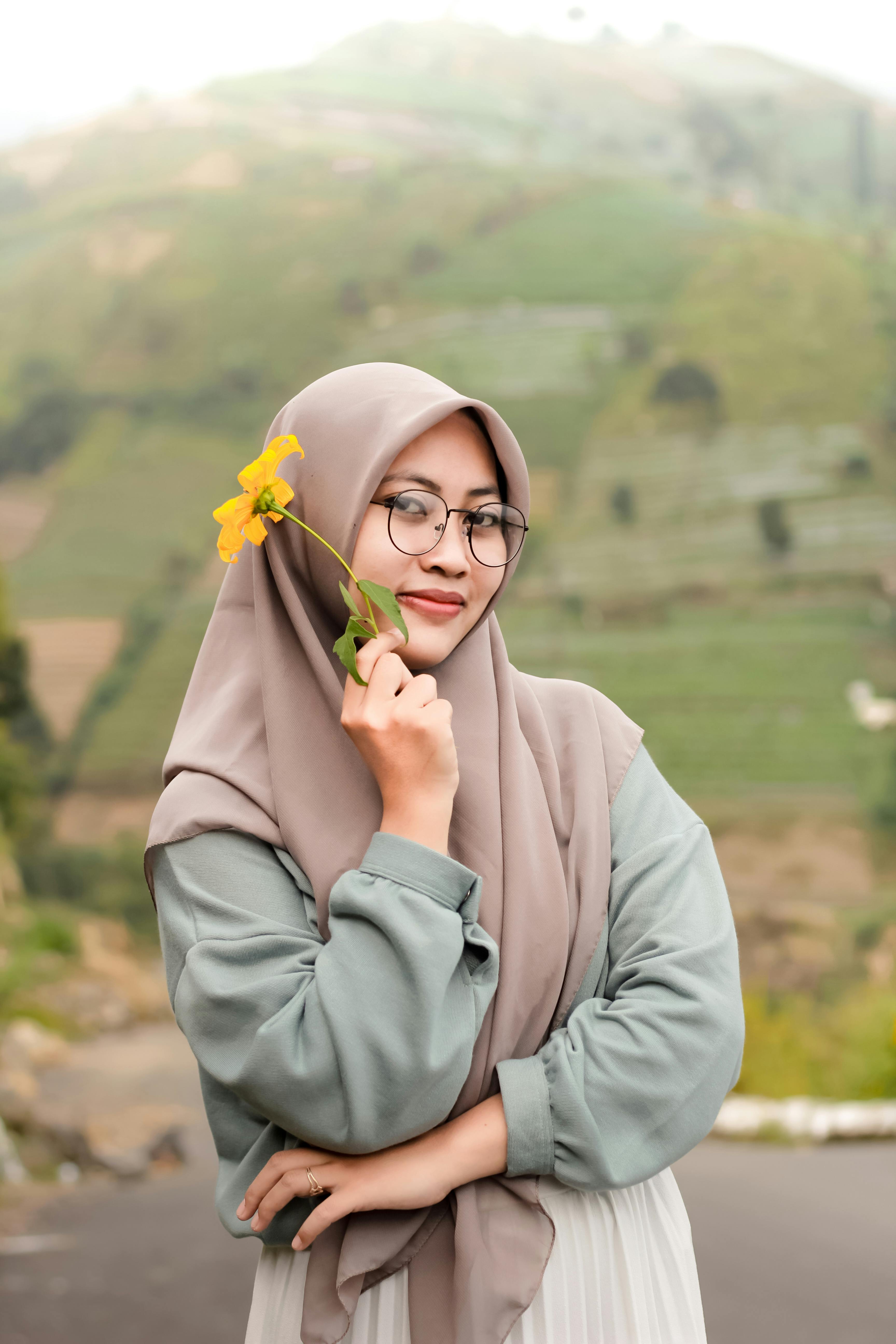 Portrait of Hijabi Girl Holding Yellow Flower · Free Stock Photo