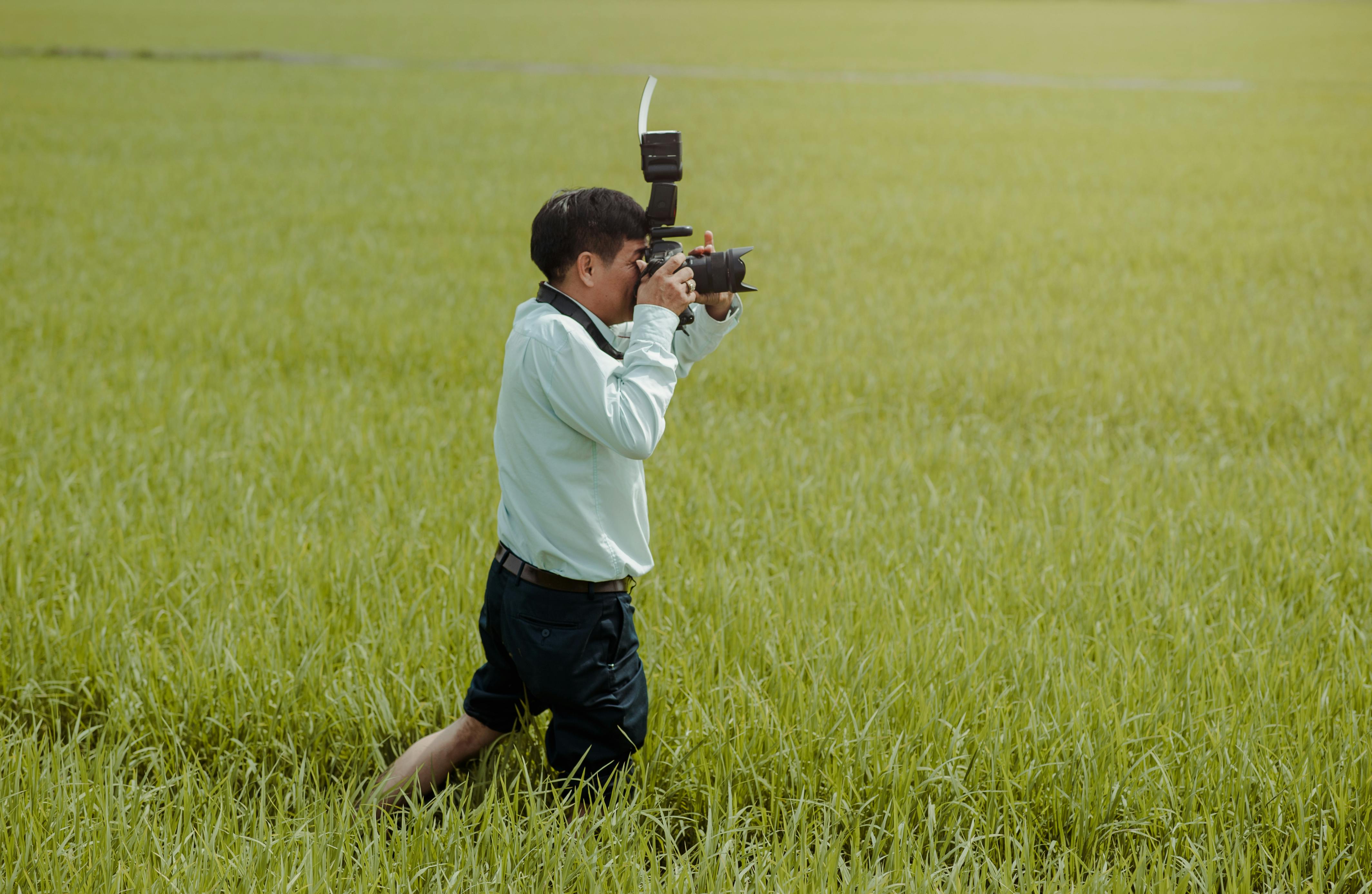 Man Standing on Rice Field Holding Camera · Free Stock Photo