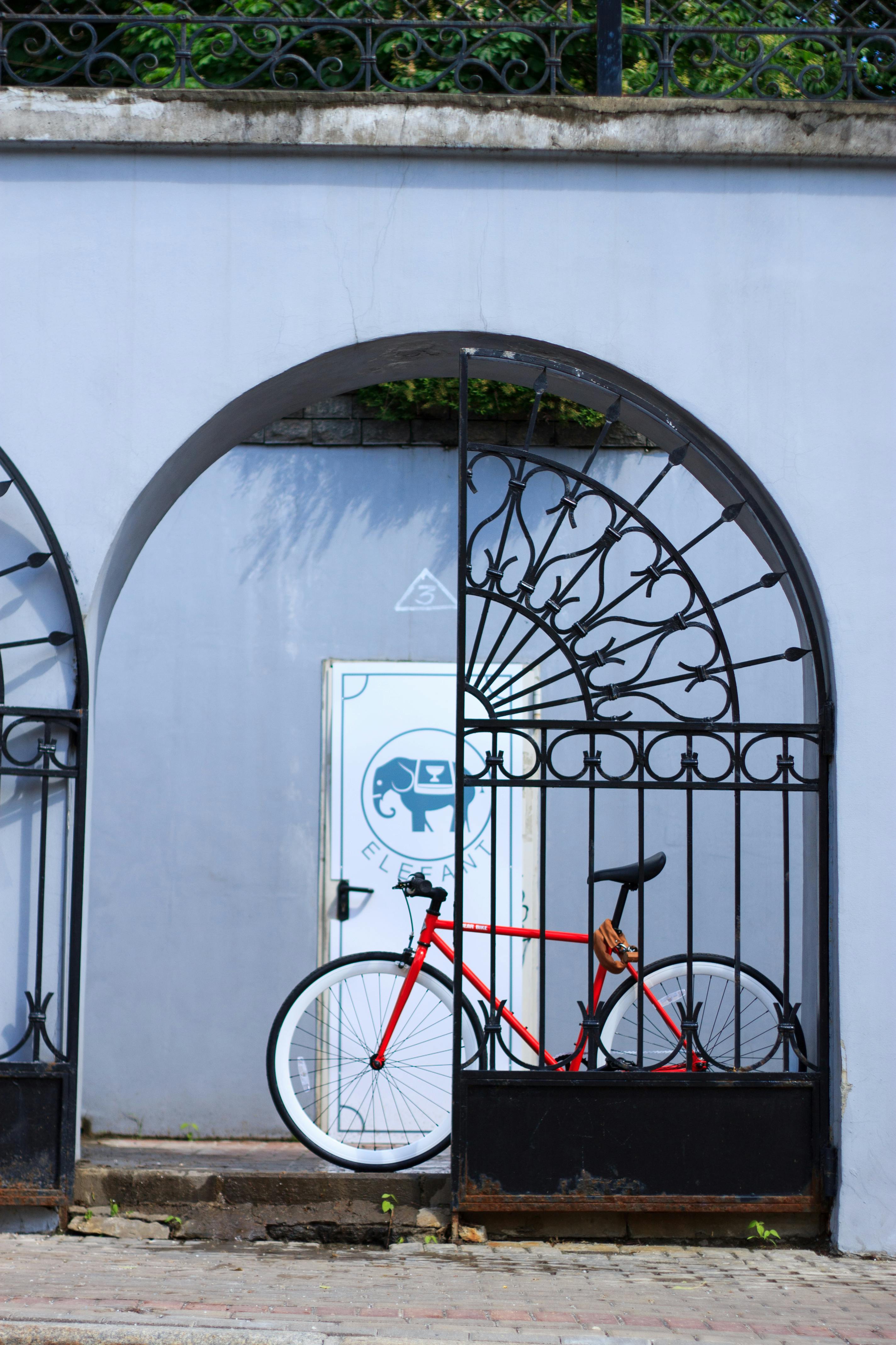 Red and Black Bicycle Behind a Metal Gate · Free Stock Photo