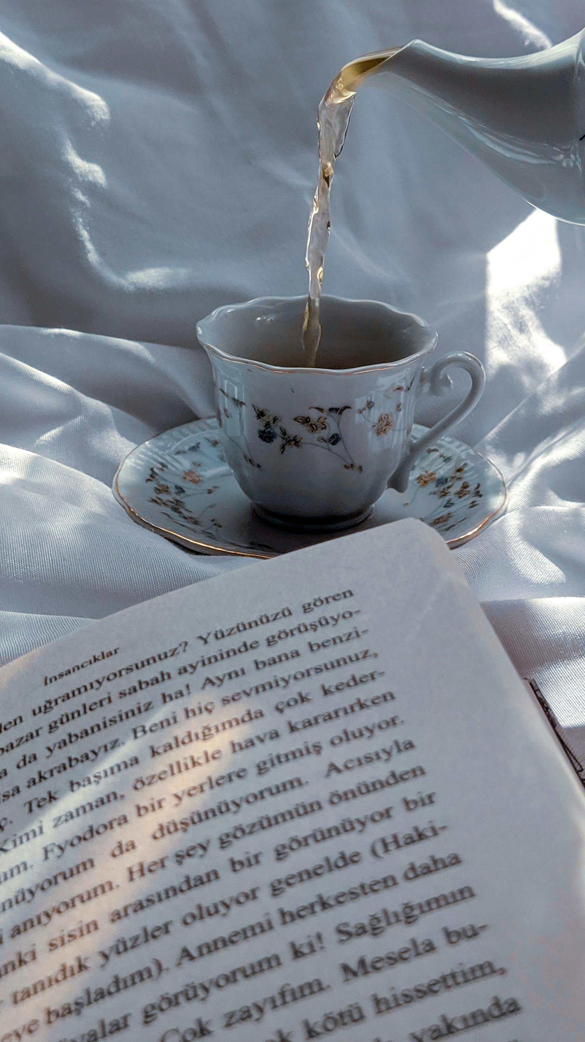 Teapot Pouring Liquid into a porcelain tea cup · Free Stock Photo