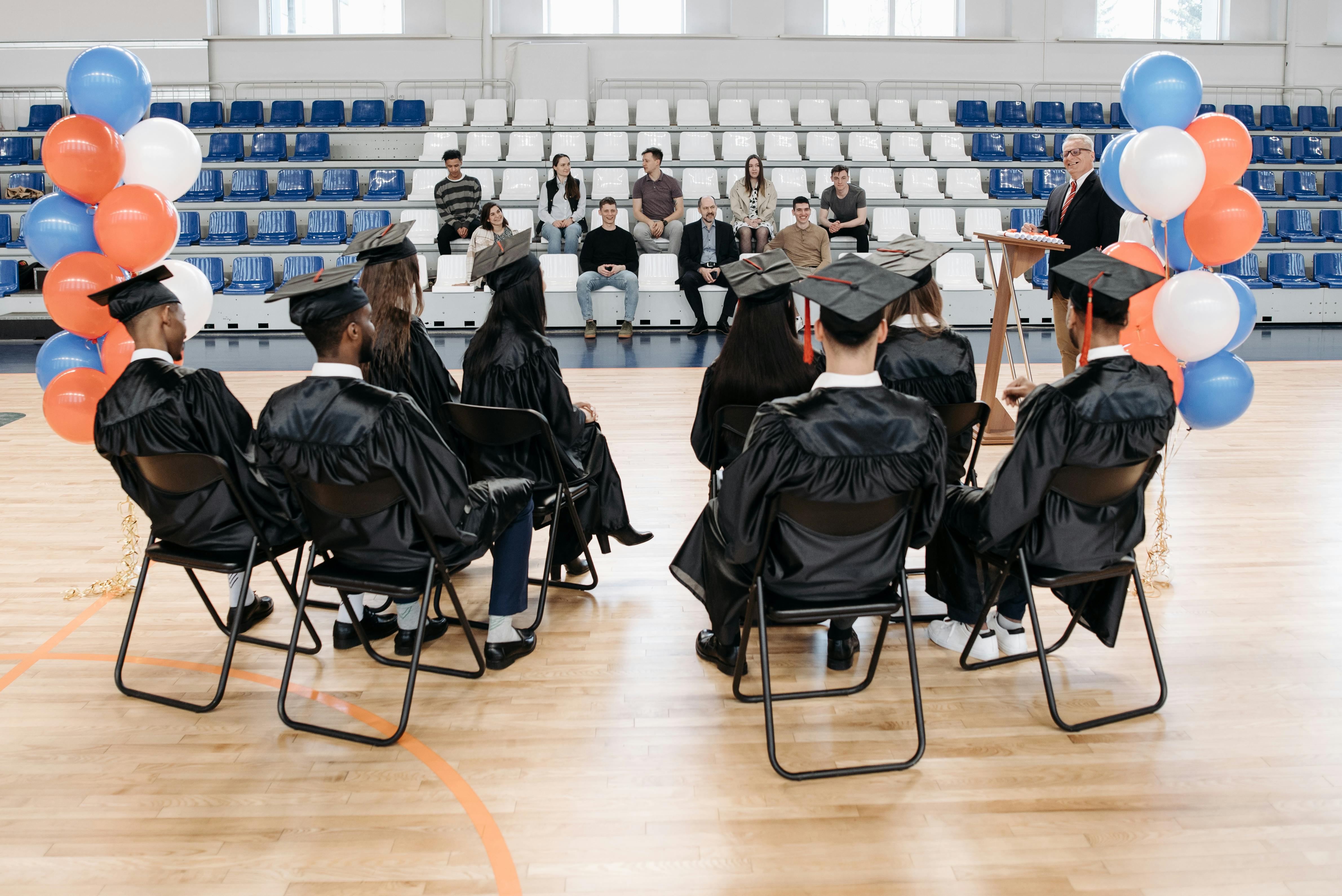 Photo of Graduates Sitting on a Folding Chair · Free Stock Photo