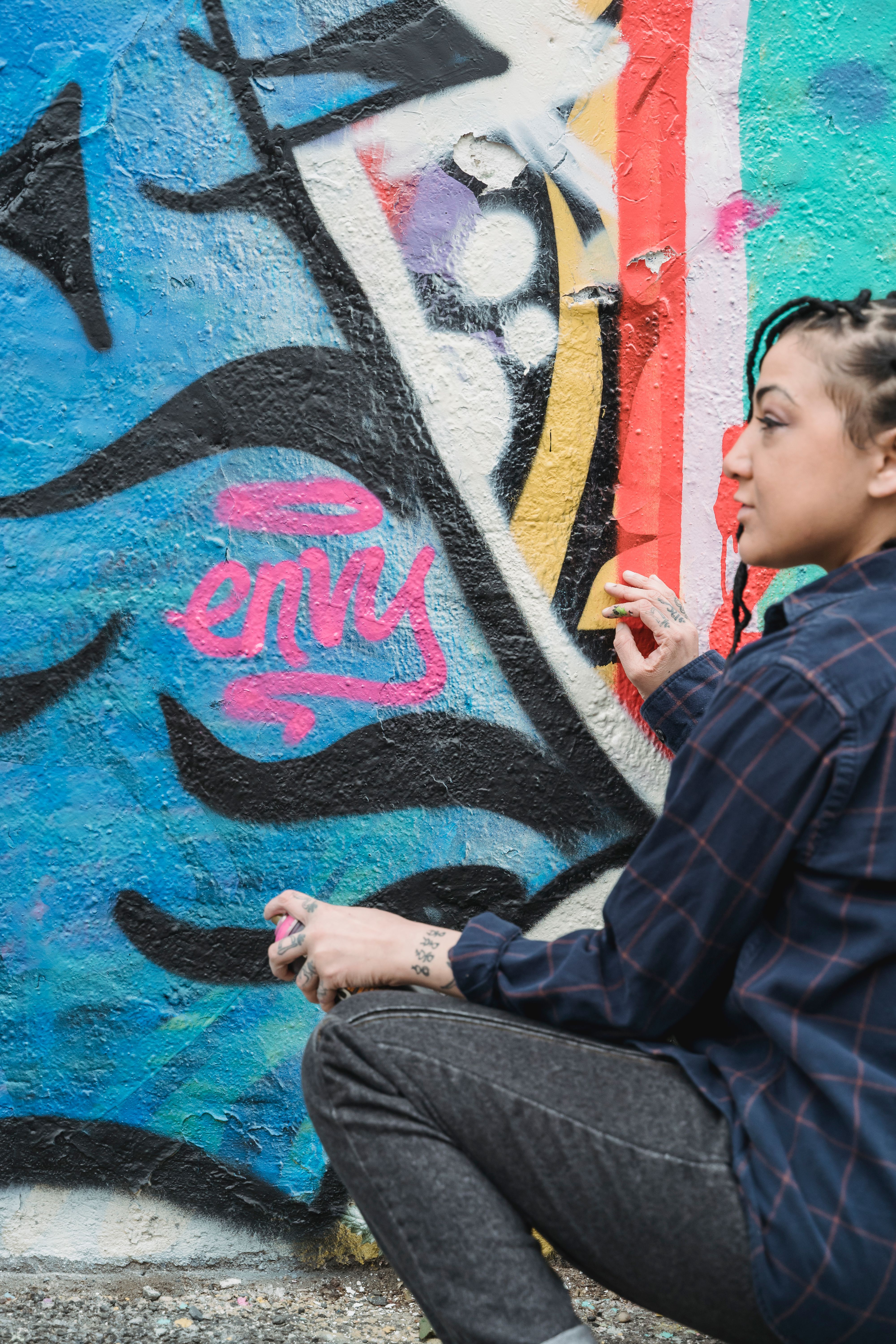 A Woman Crouching by a Graffiti on a Wall · Free Stock Photo