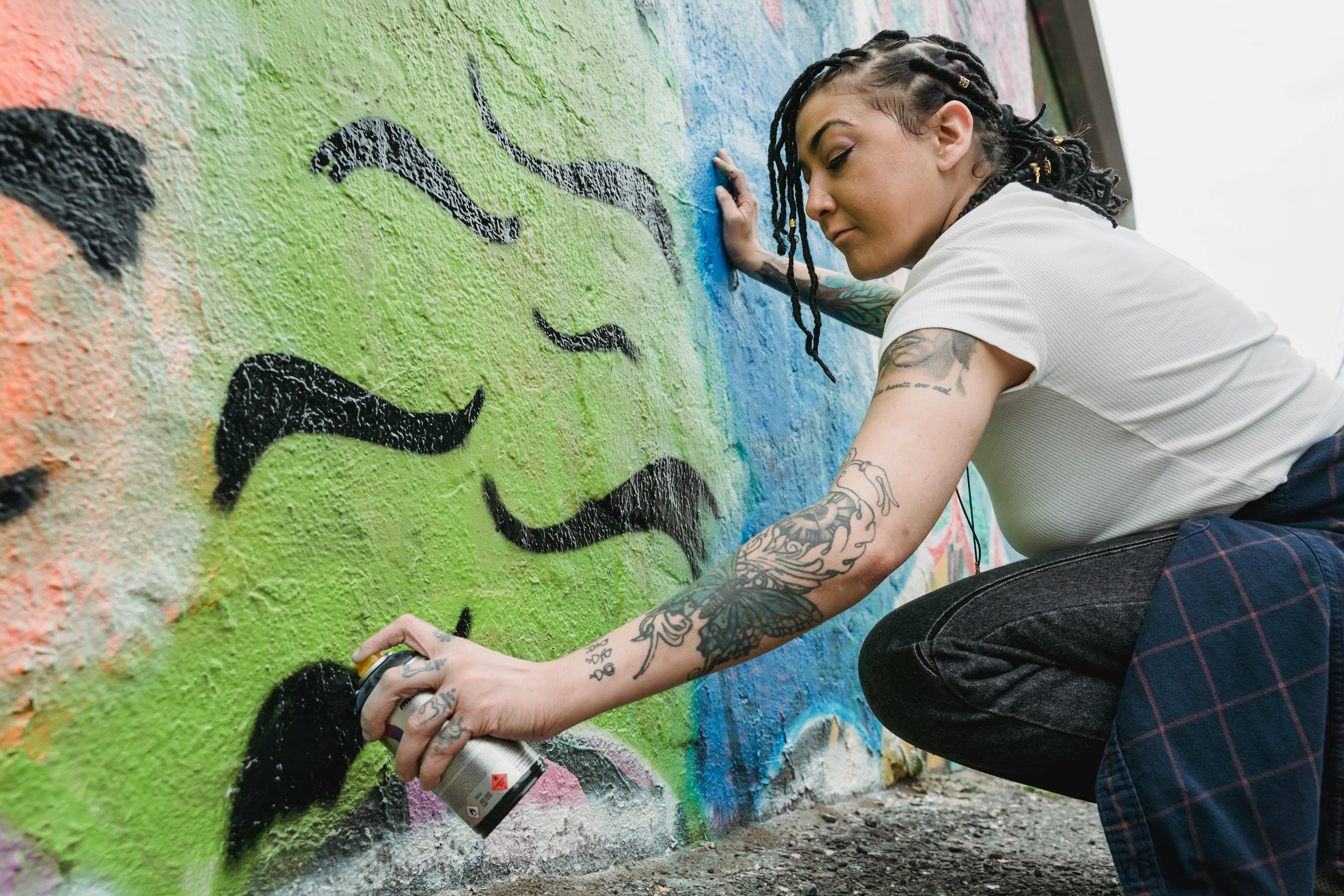 A Woman Doing Graffiti on a Wall Using a Spray Paint · Free Stock Photo