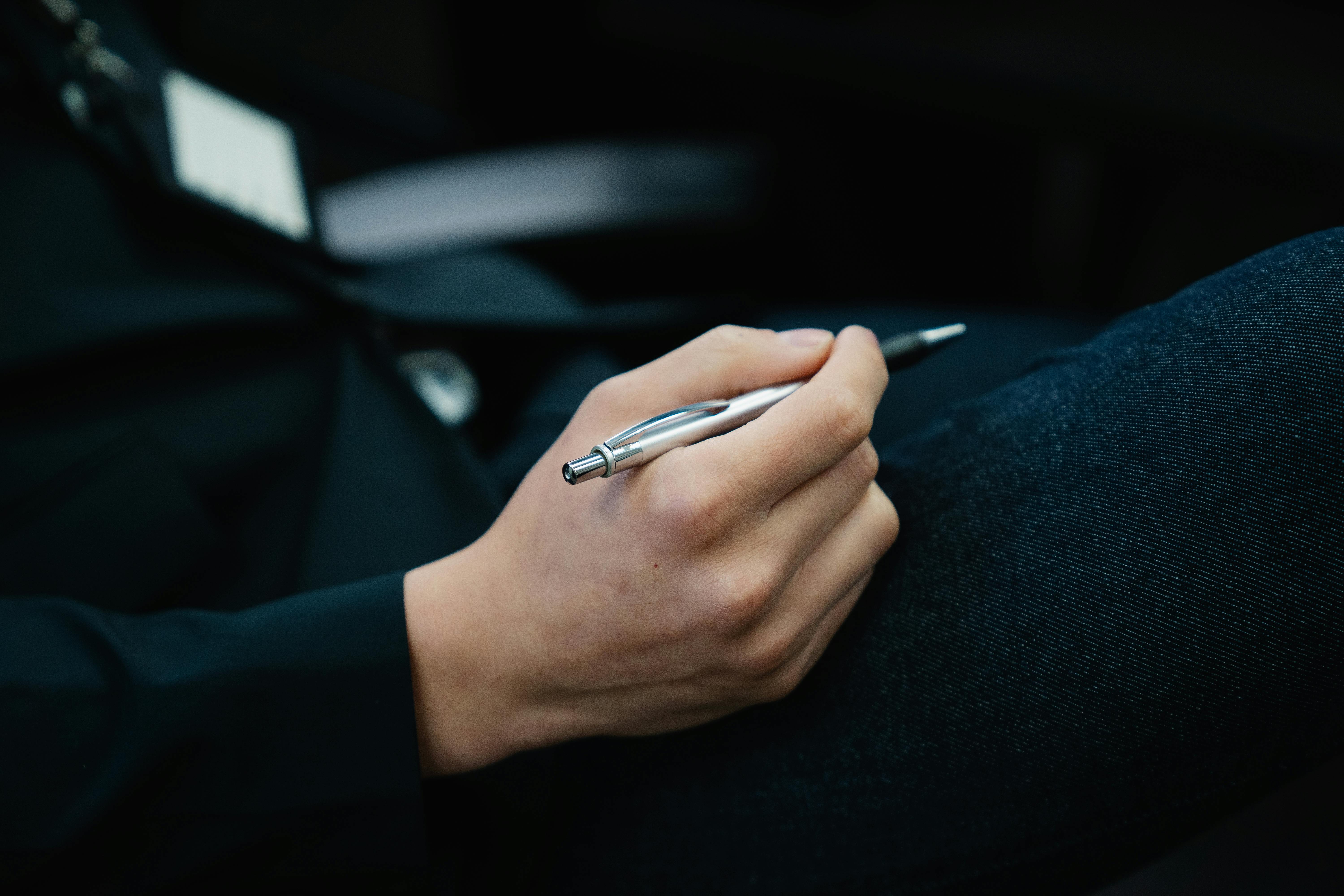 Close-Up Photo of a Person's Hand Holding a Silver Pen · Free Stock Photo