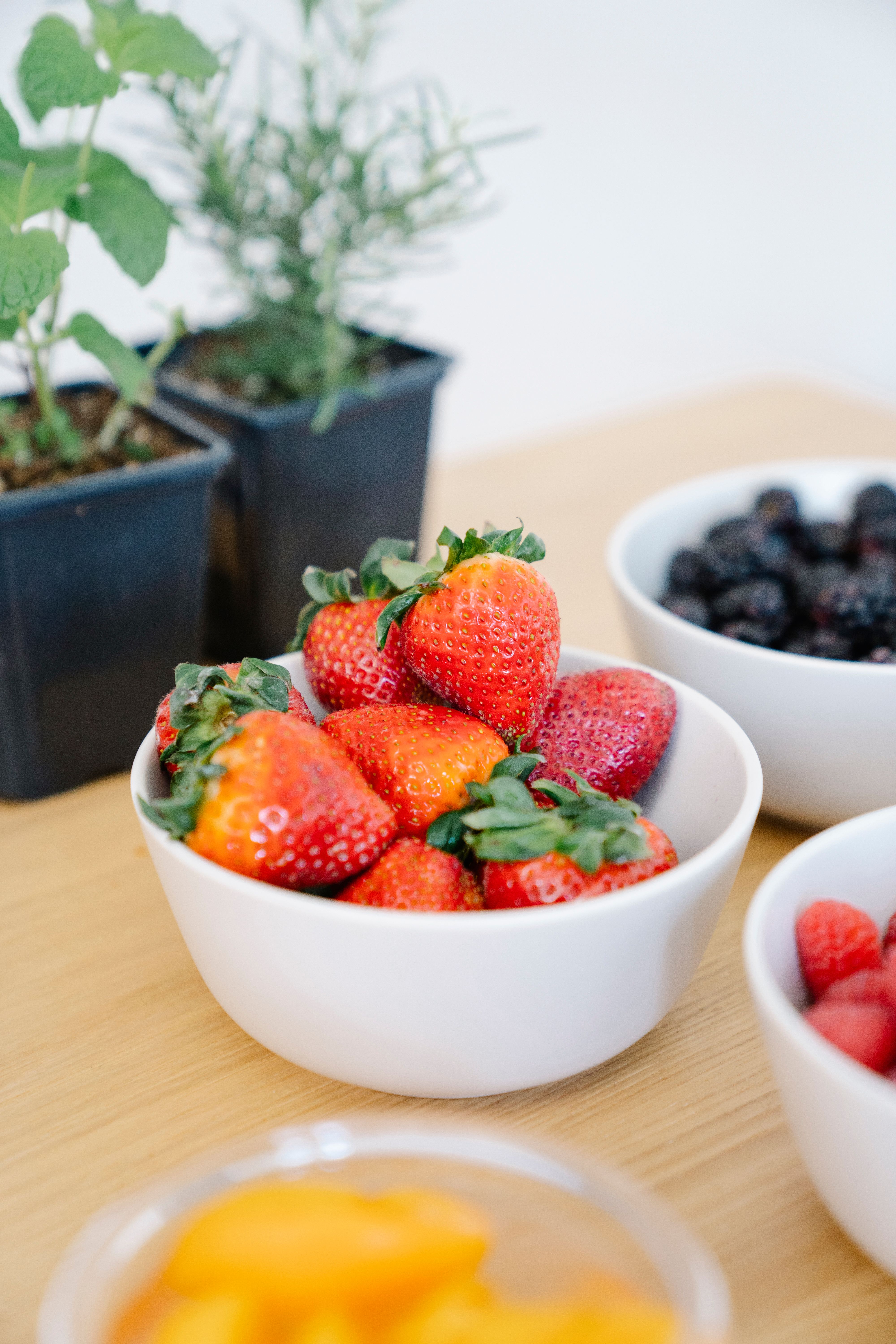 Fruits in Bowls and Potted Plants on Table · Free Stock Photo