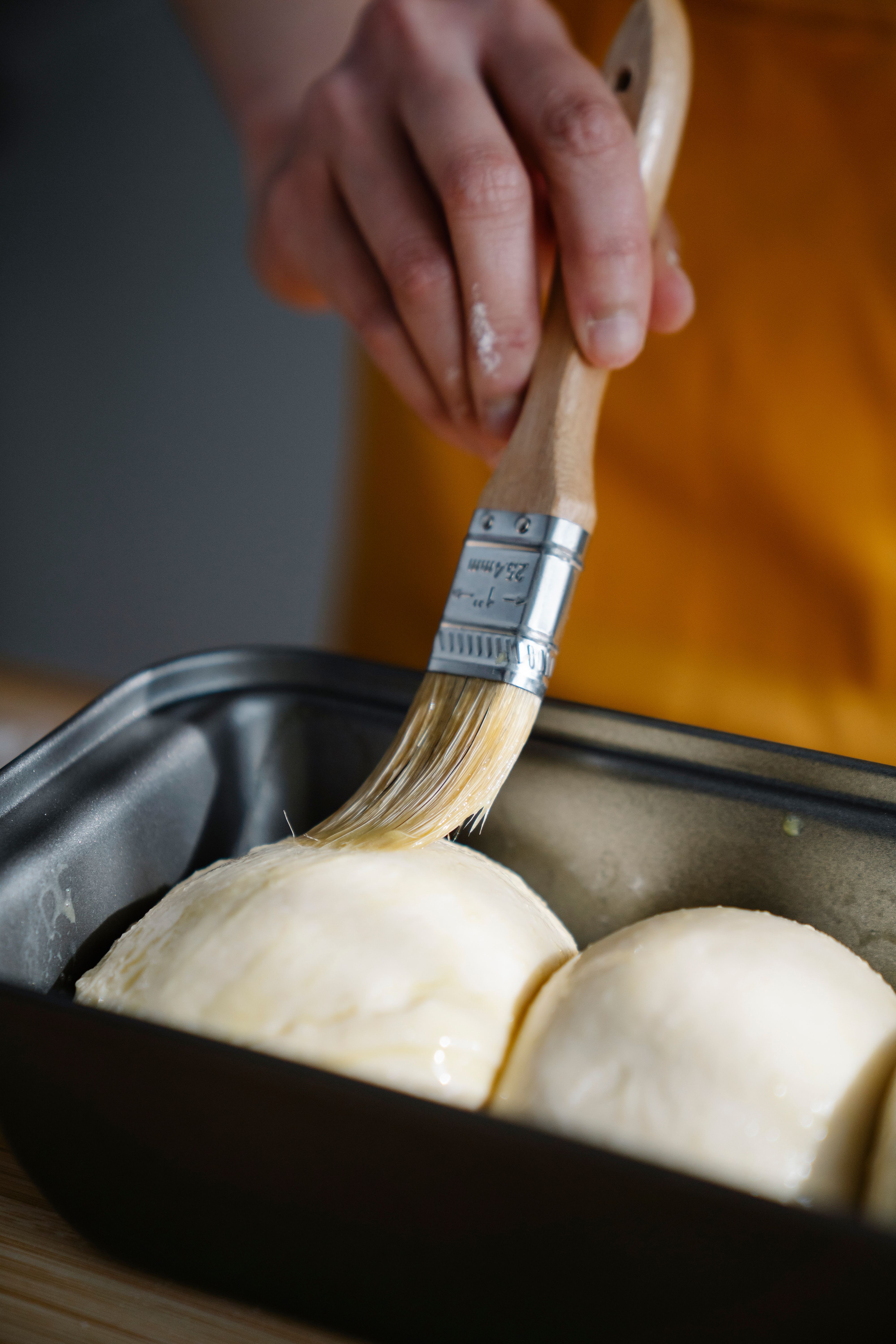 Close Up Photo of a Person Spreading Oil on Dough · Free Stock Photo