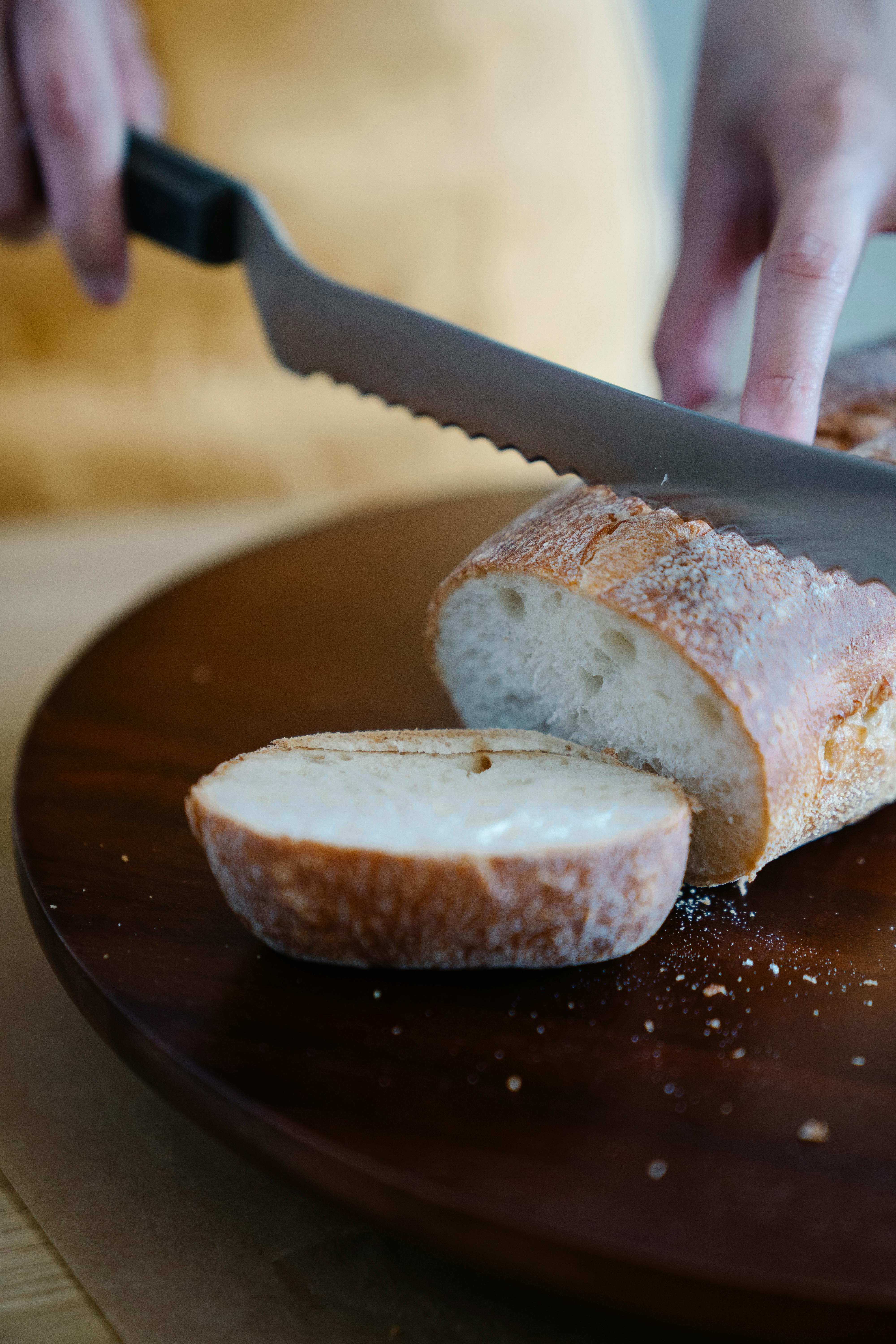 Person Slicing Bread with a Knife · Free Stock Photo