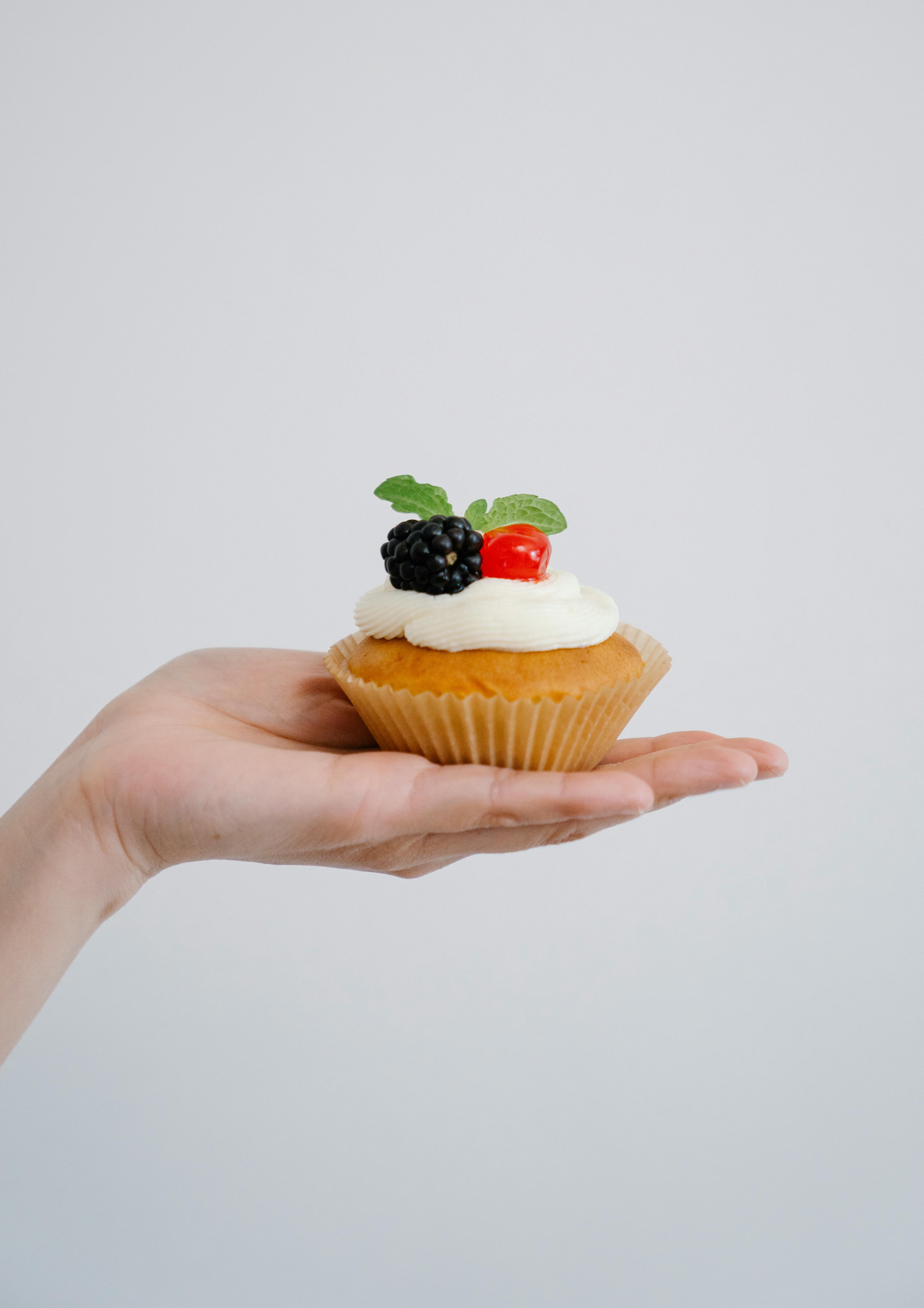 Close-Up Shot of a Person Holding a Delicious Cupcake · Free Stock Photo