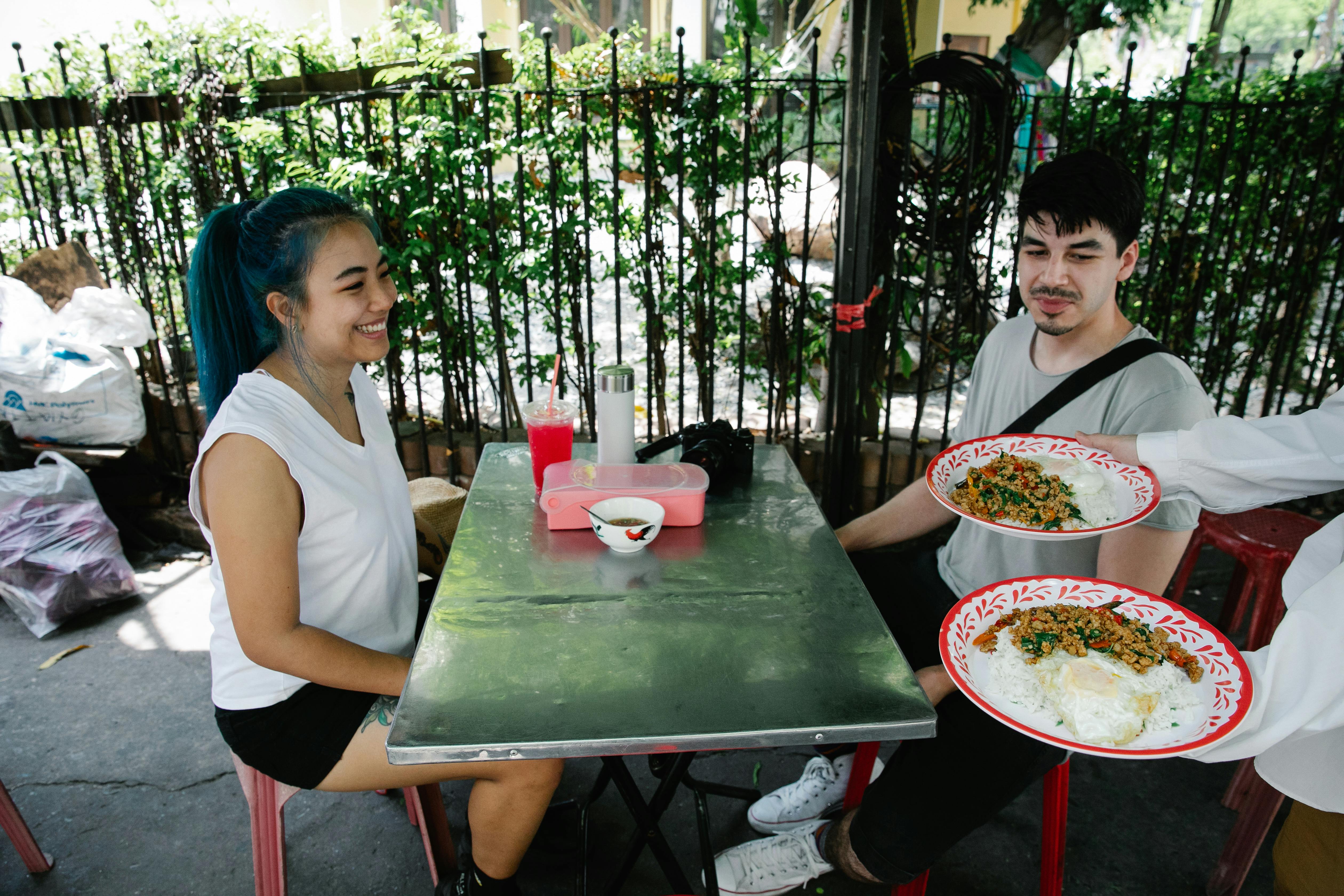 Faceless waiter serving food to diverse couple · Free Stock Photo