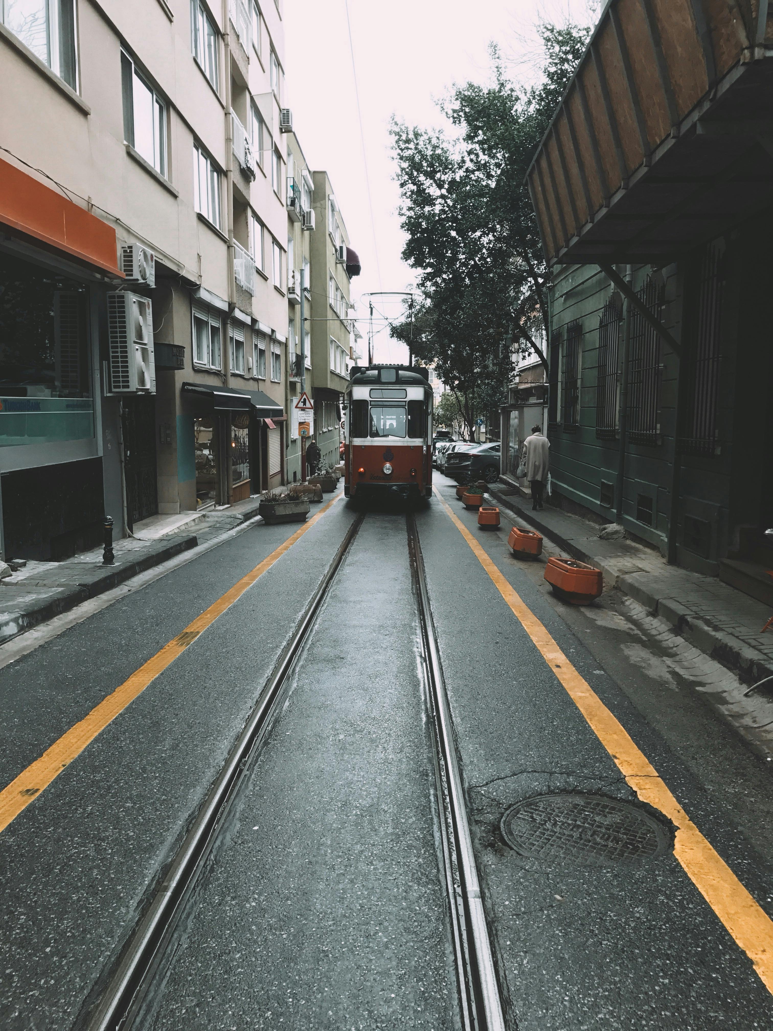Tramway riding on rail in narrow street · Free Stock Photo