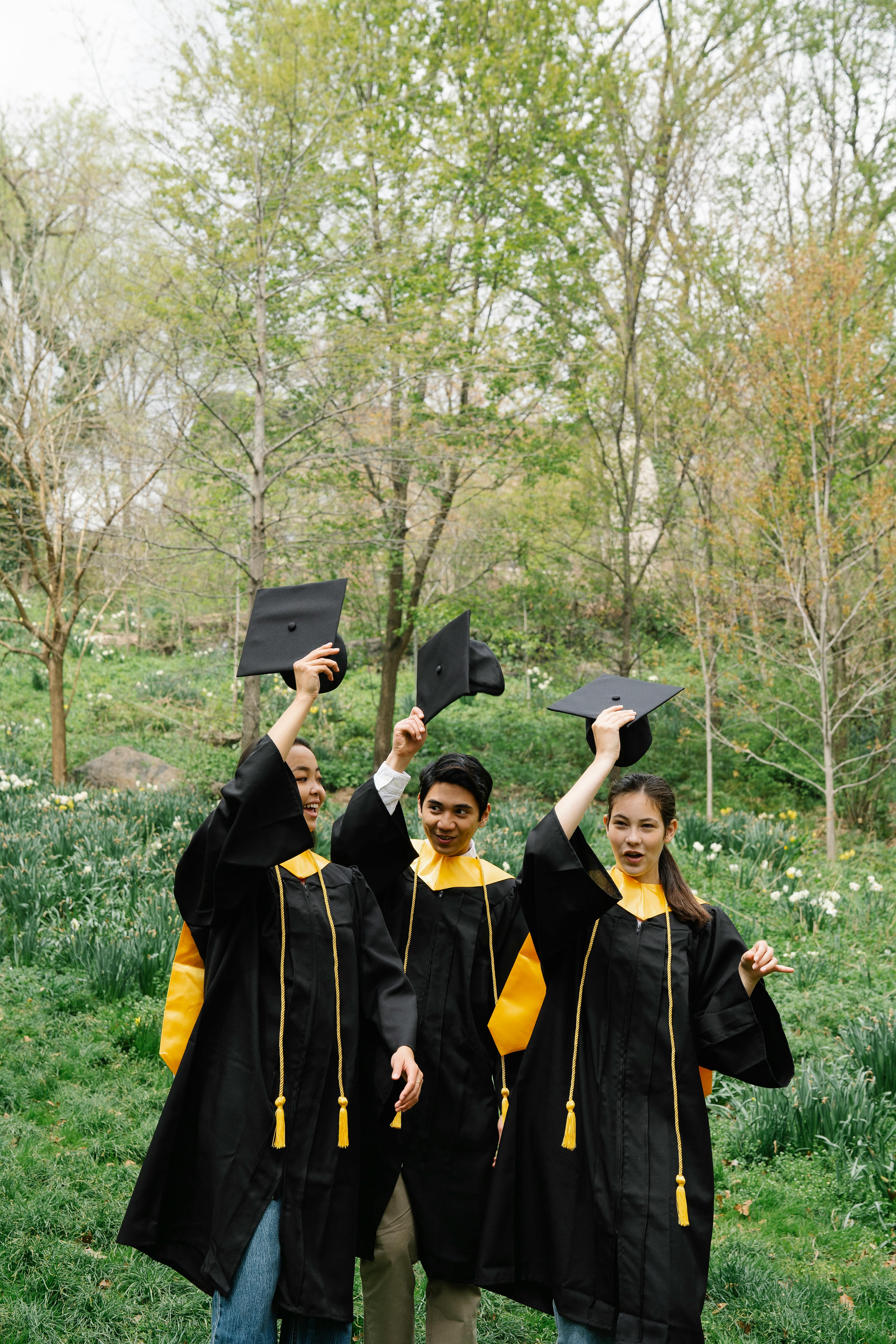 Graduates with Raised Mortarboards · Free Stock Photo