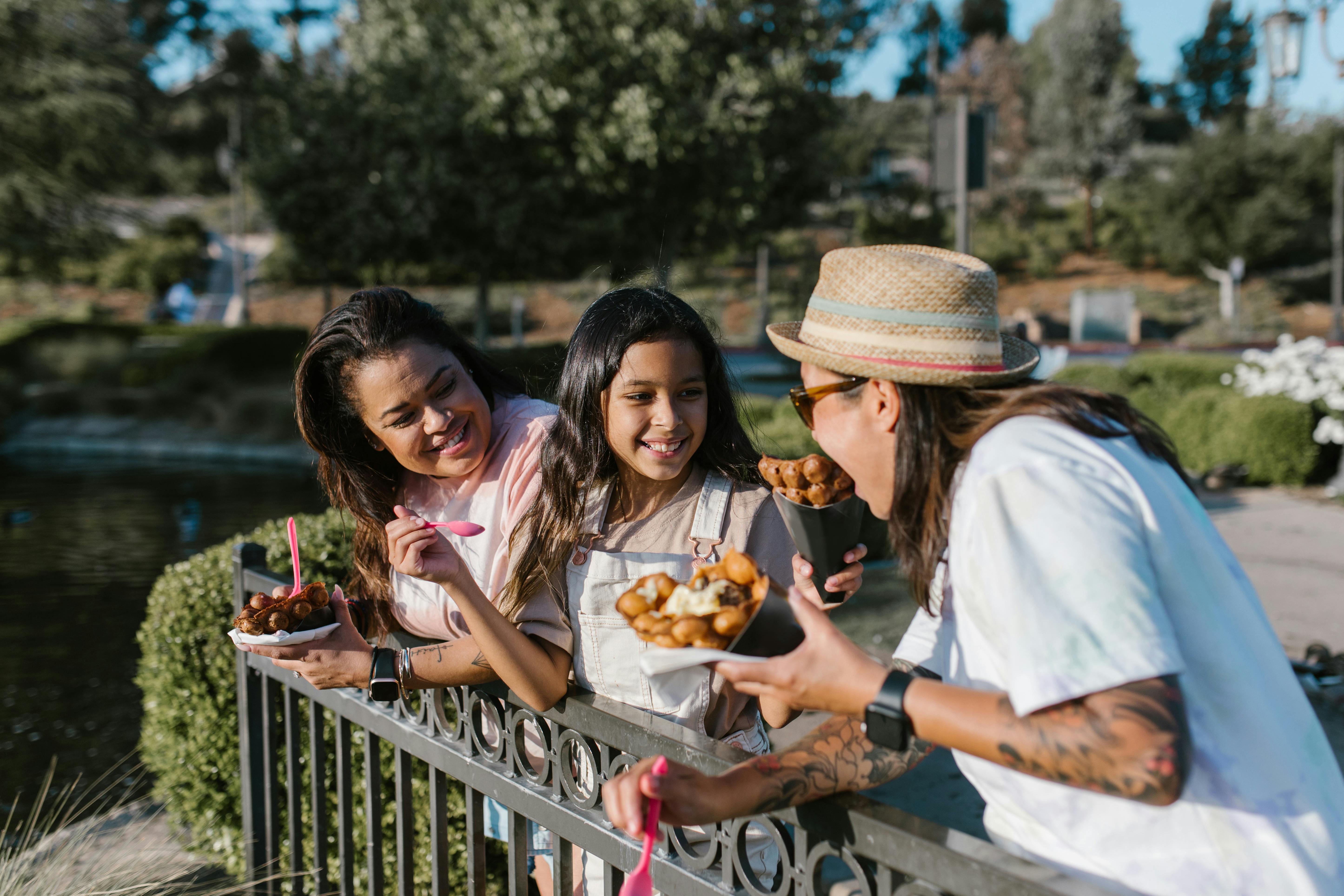 A Family Eating Snacks while Leaning on a Fence · Free Stock Photo