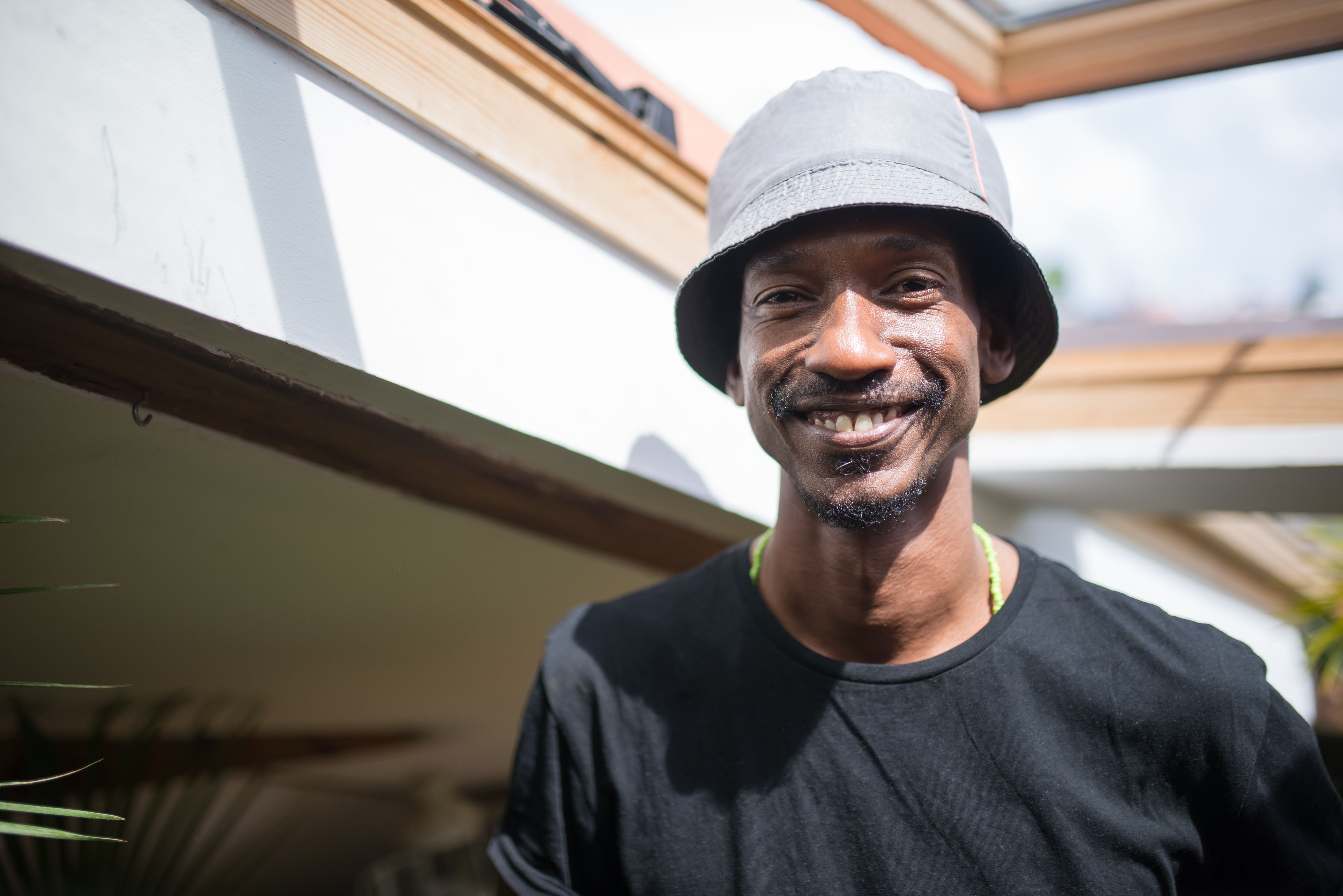 Portrait of Sitting Smiling Man with Bucket Hat · Free Stock Photo