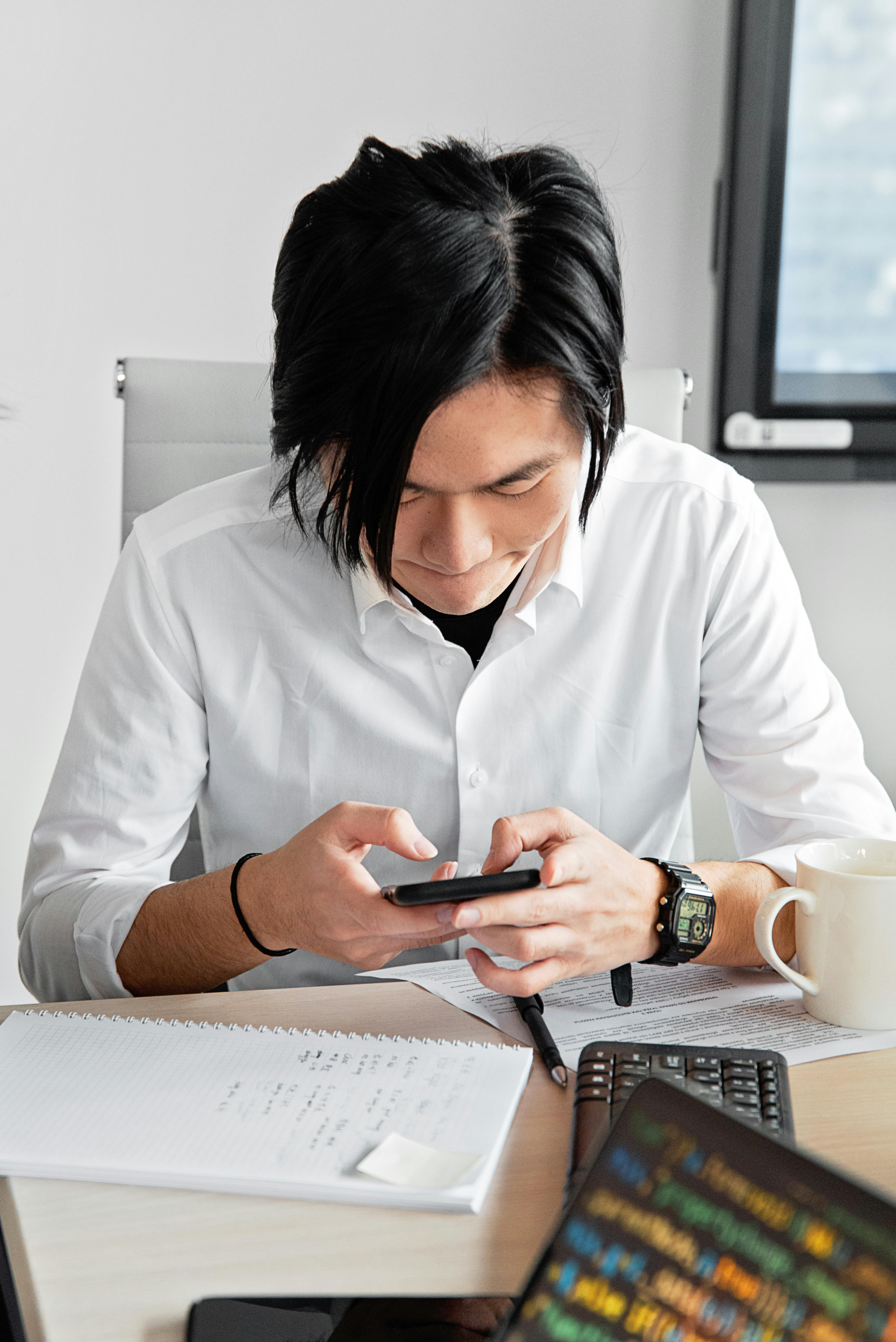 Man Sitting in his Office and Looking at his Phone · Free Stock Photo