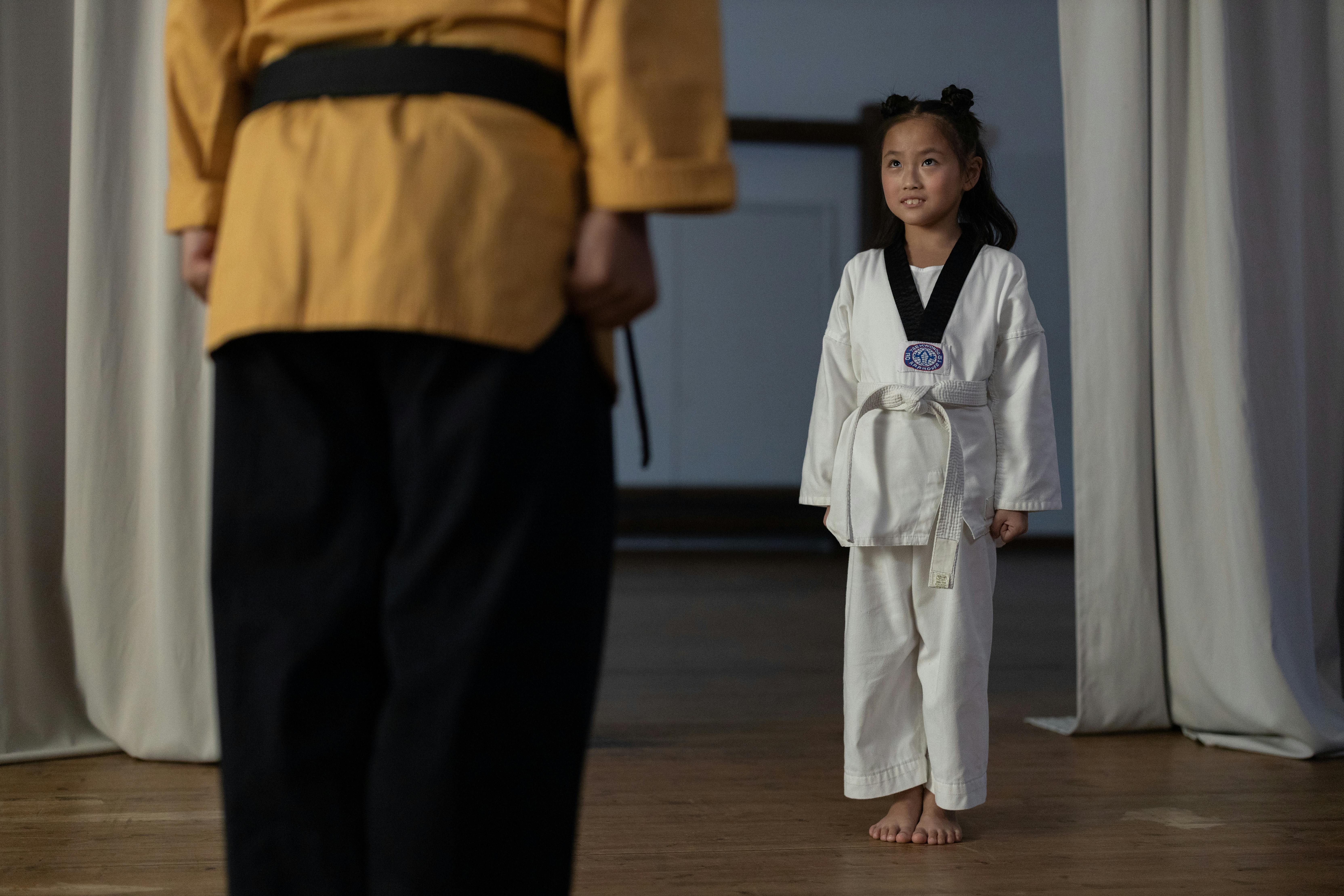 A Girl in White Dobok Standing Barefooted in Front of a Person · Free ...