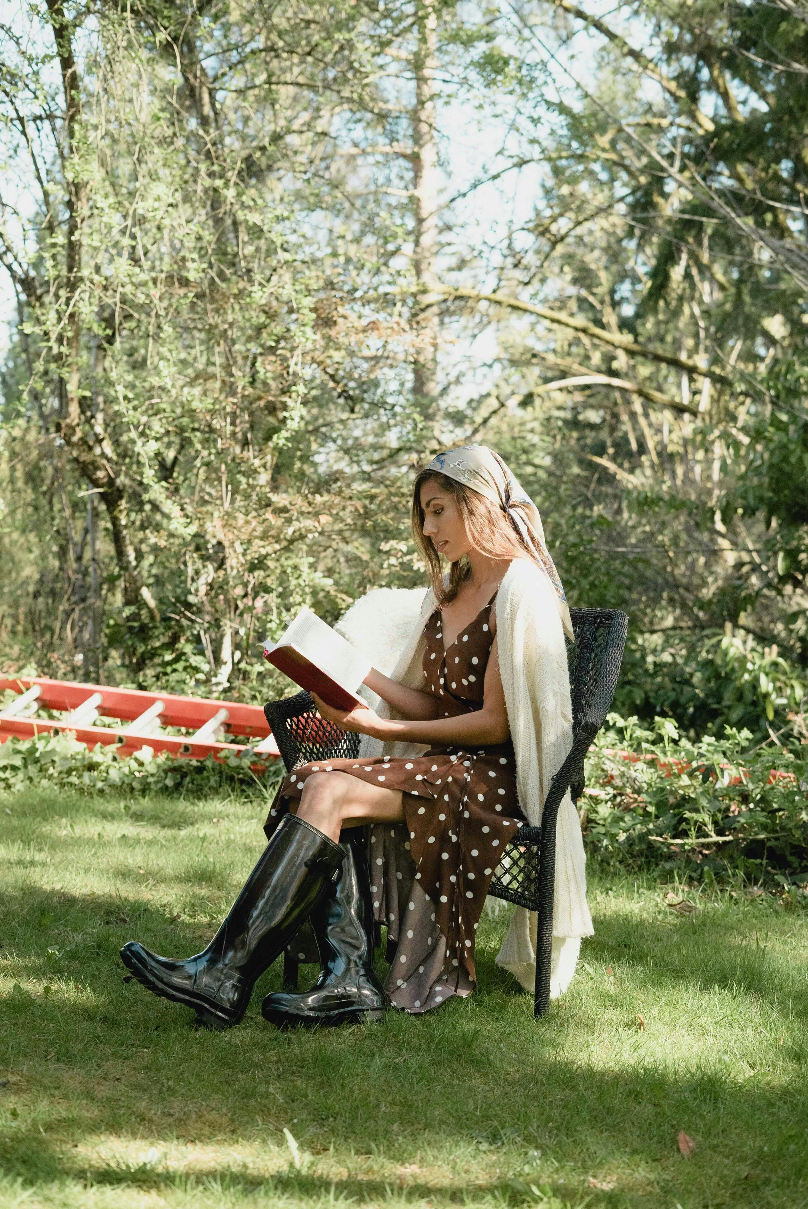 A Woman Wearing a Polka Dot Dress and Rubber Boots Reading a Book ...