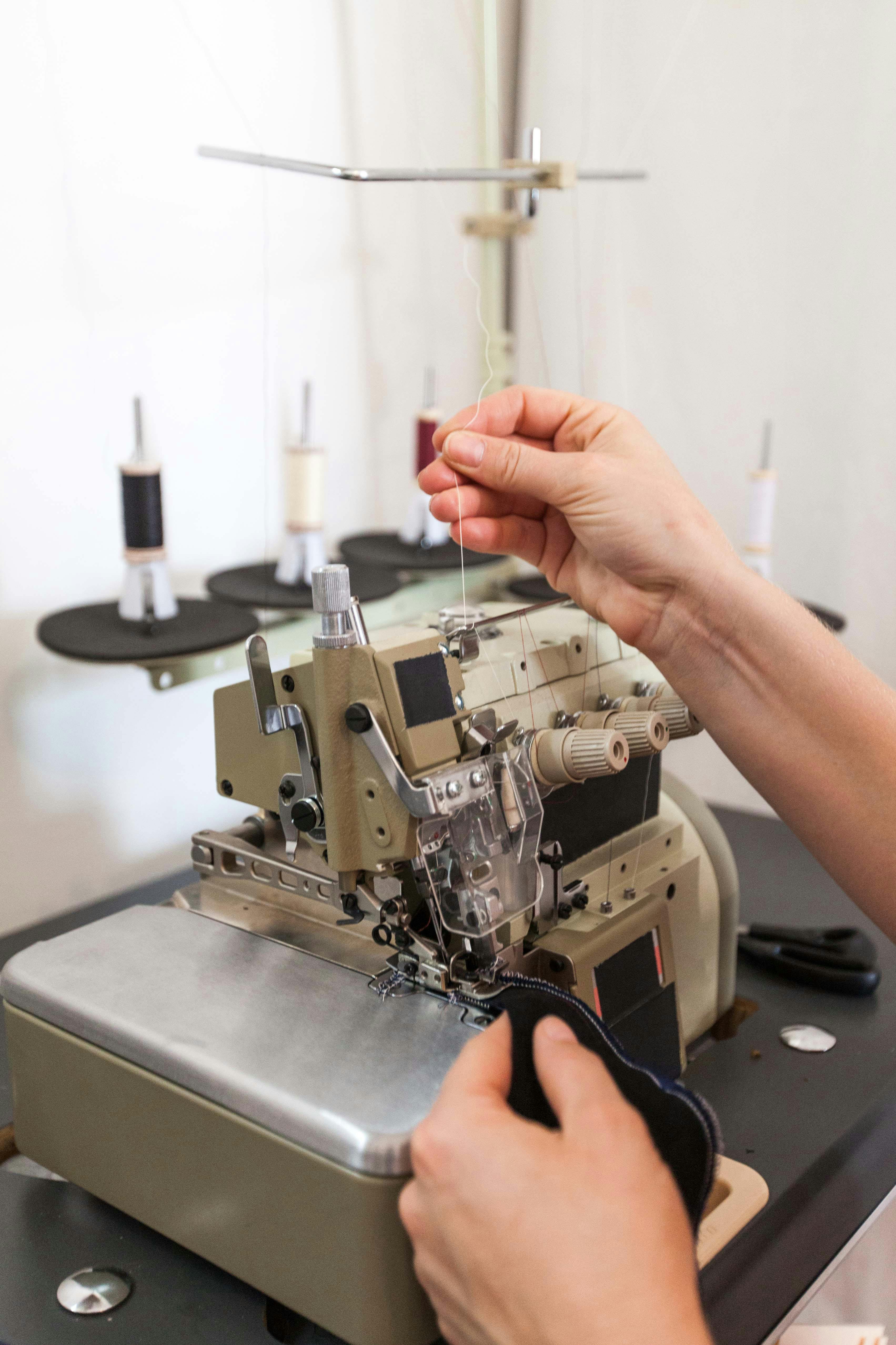 Hand Holding Textile Near Sewing Machine · Free Stock Photo