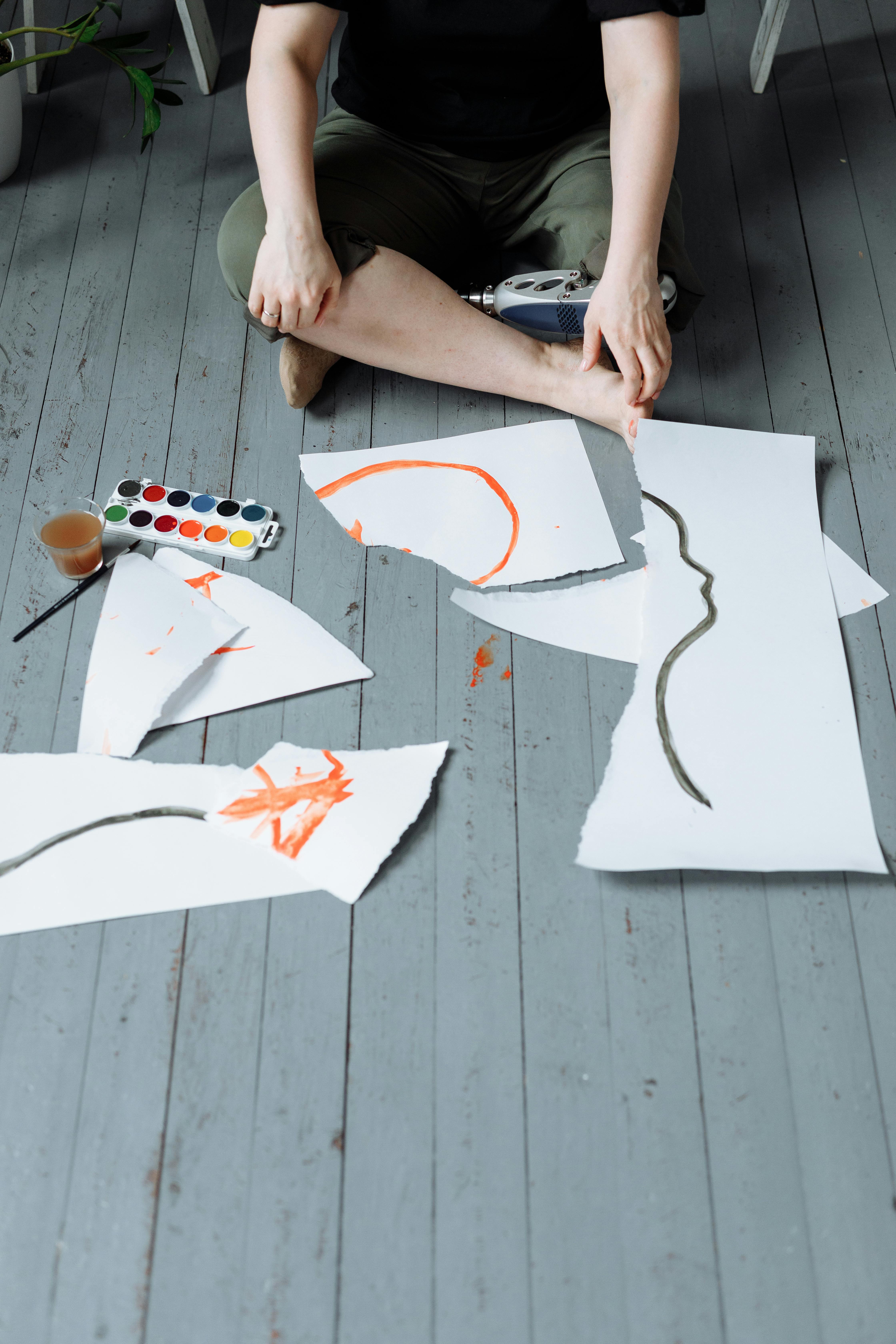 An Artist Sitting beside a Ripped Painting on the Floor · Free Stock Photo