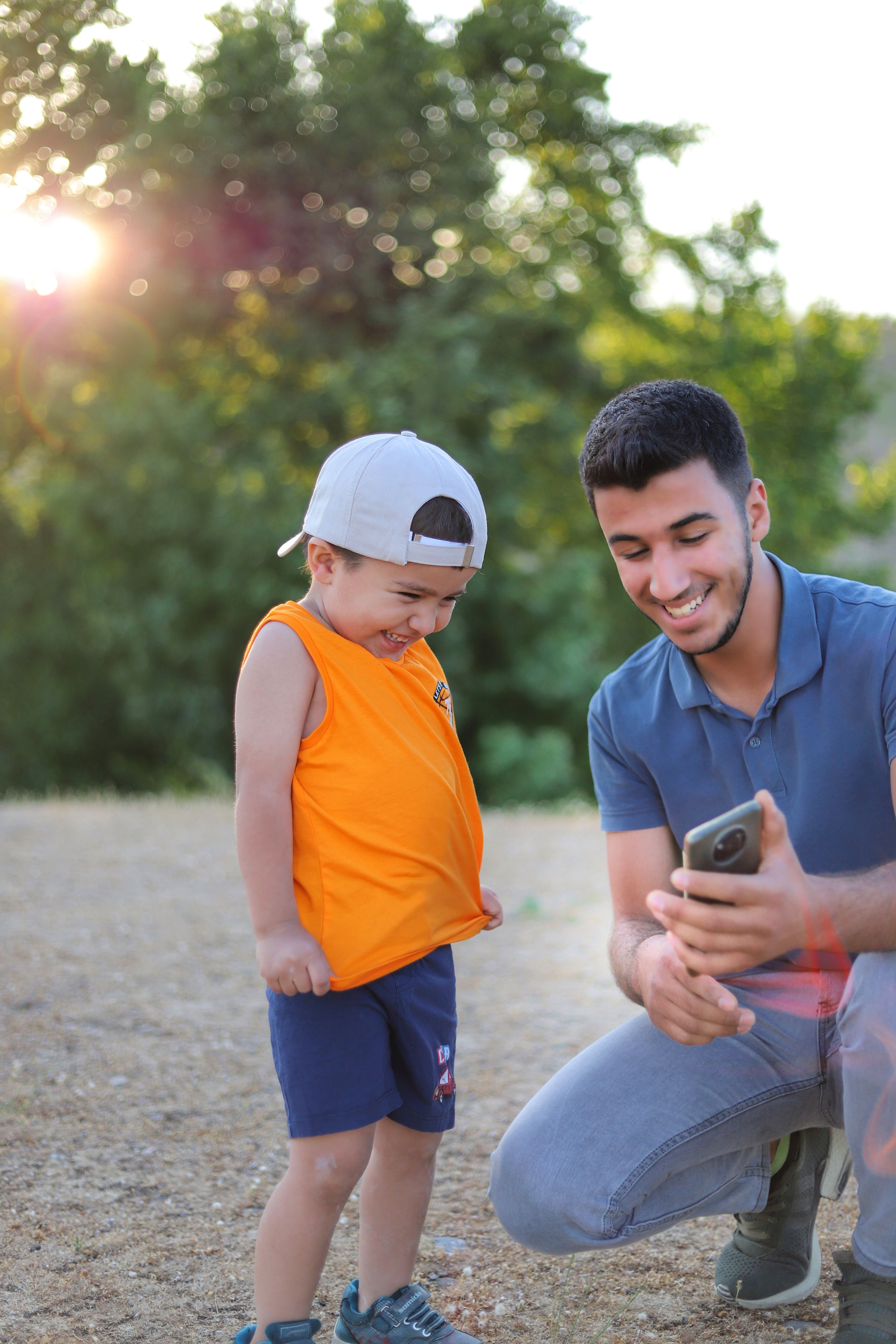 A Man and Young Boy Looking at the Smartphone Together · Free Stock Photo