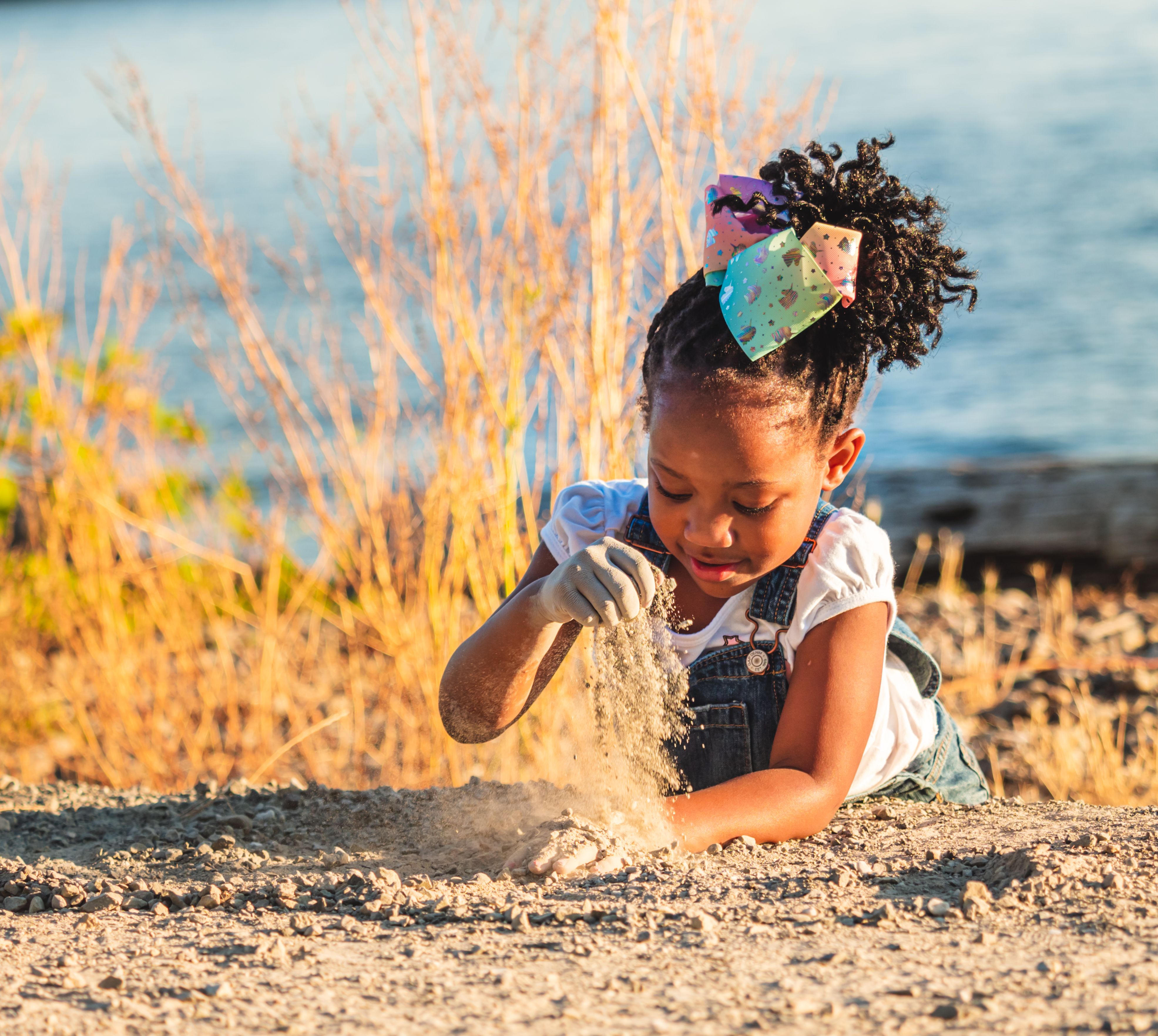 A Young Girl Lying Down while Playing a Sand · Free Stock Photo