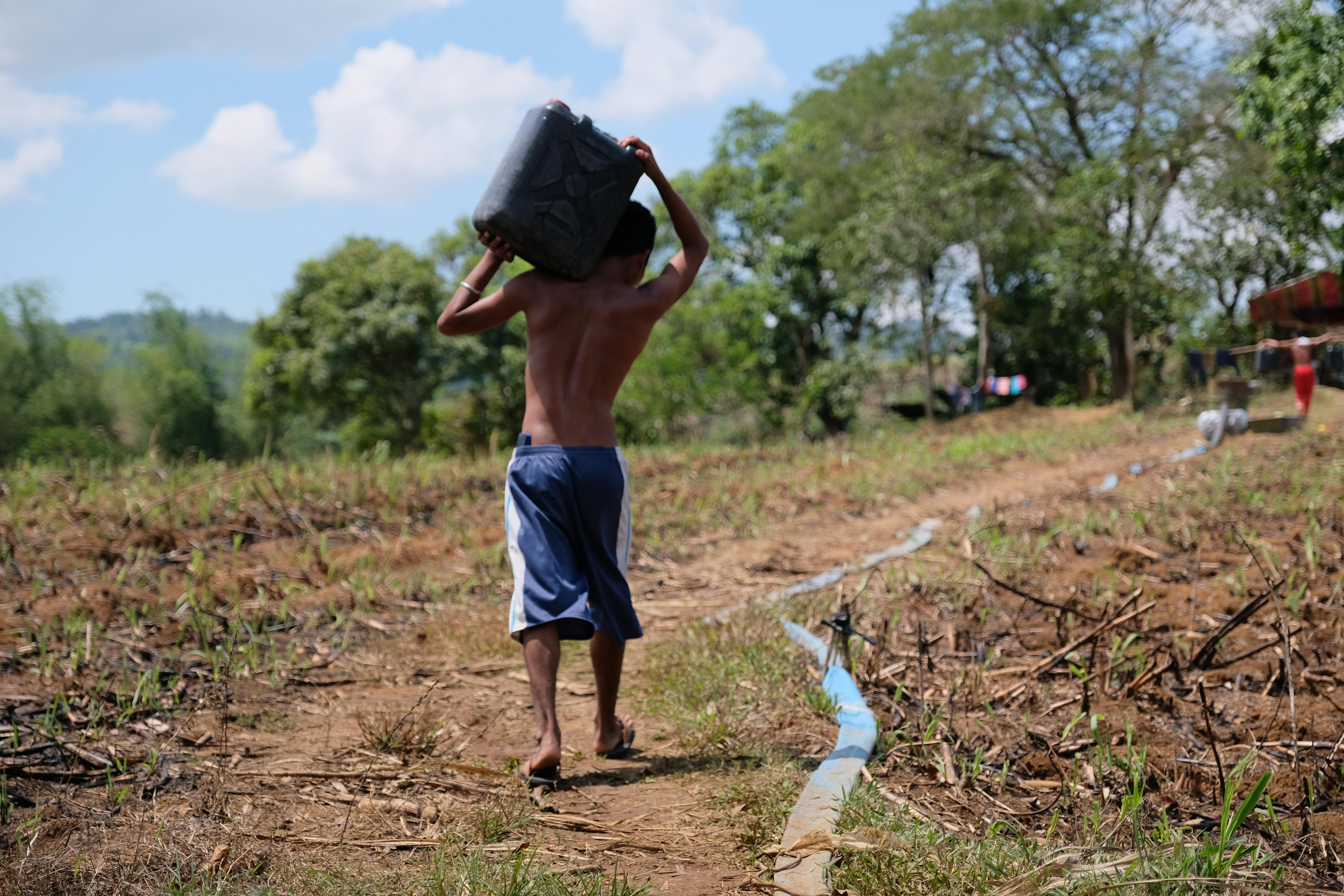 A Shirtless Man Carrying a Black Container · Free Stock Photo