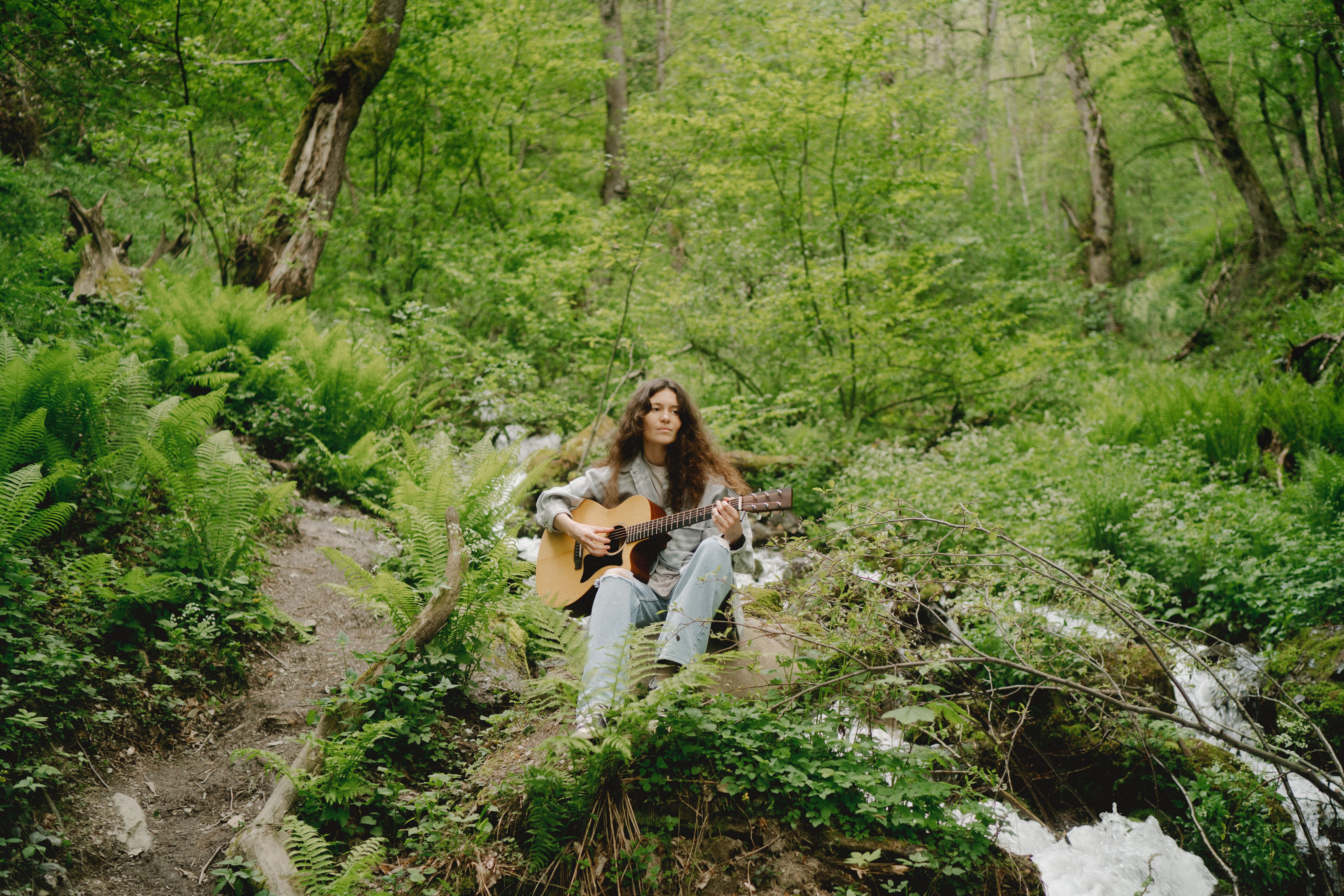 A Woman Playing the Guitar in the Woods · Free Stock Photo