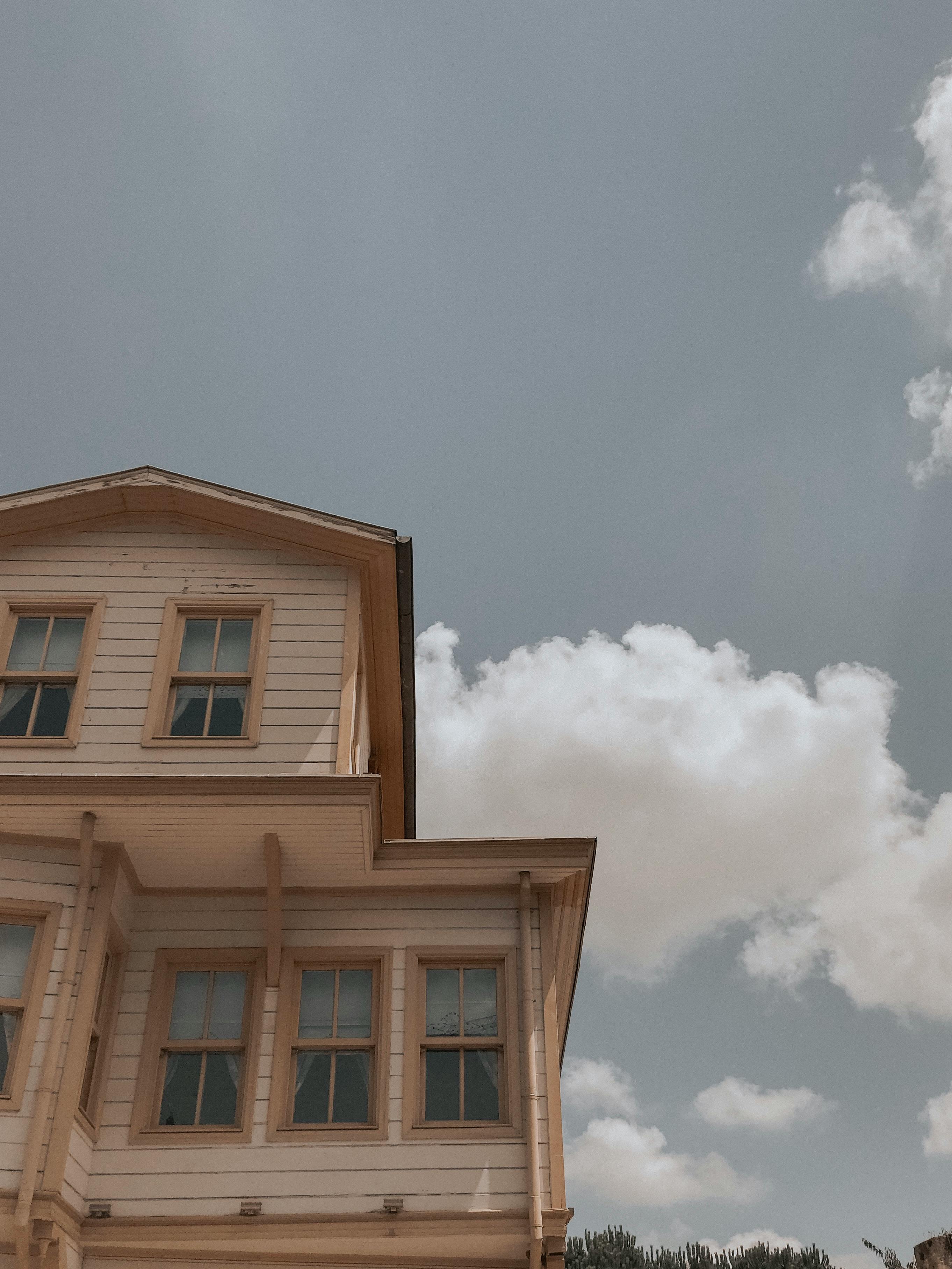 Brown Wooden House With Glass Windows Under Gray Sky With White Clouds ...