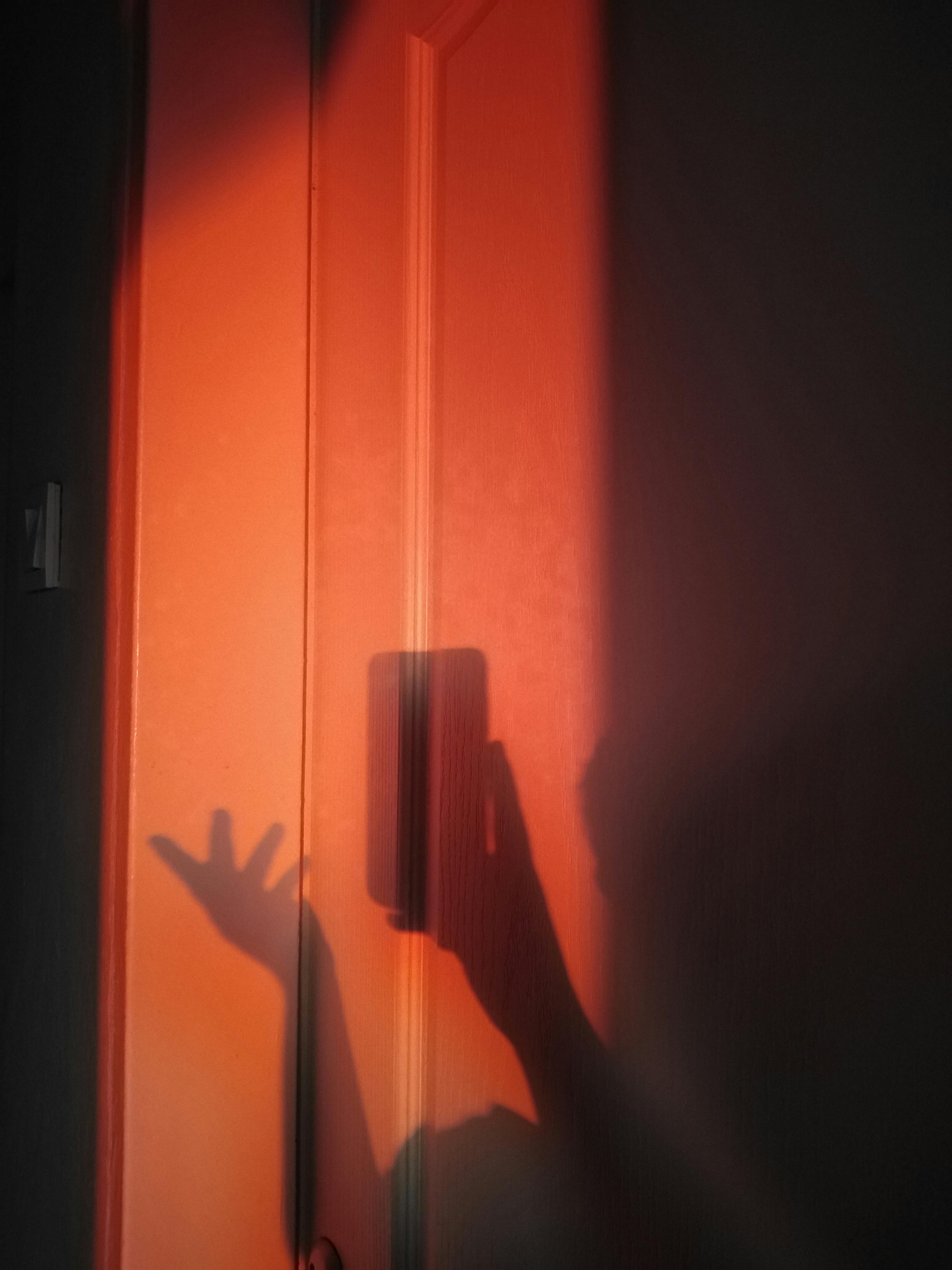 Shadow of Person Standing Near a Wooden Door Holding Cellphone · Free ...