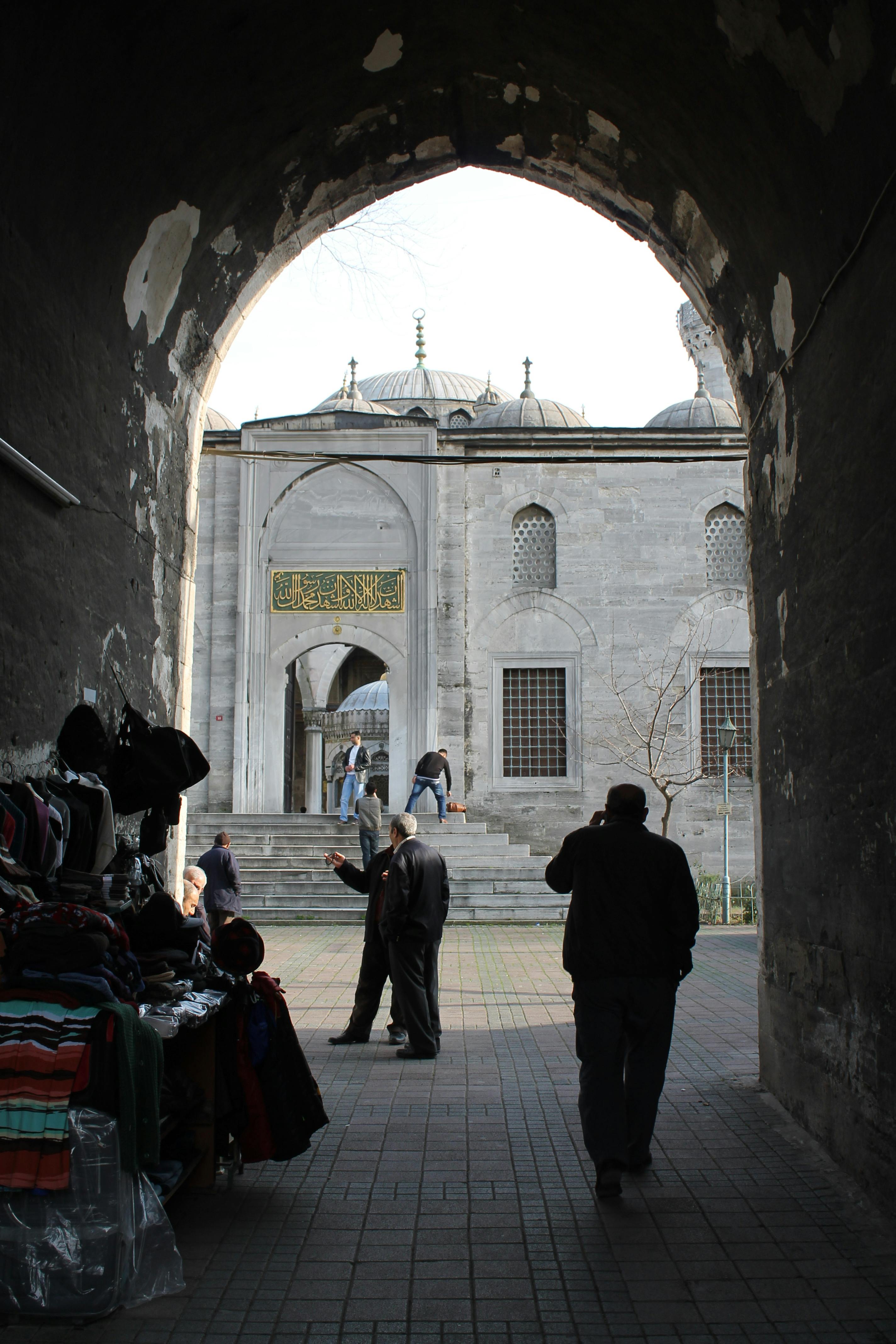 People Walking Near the Stall on a Hallway of an Arch · Free Stock Photo