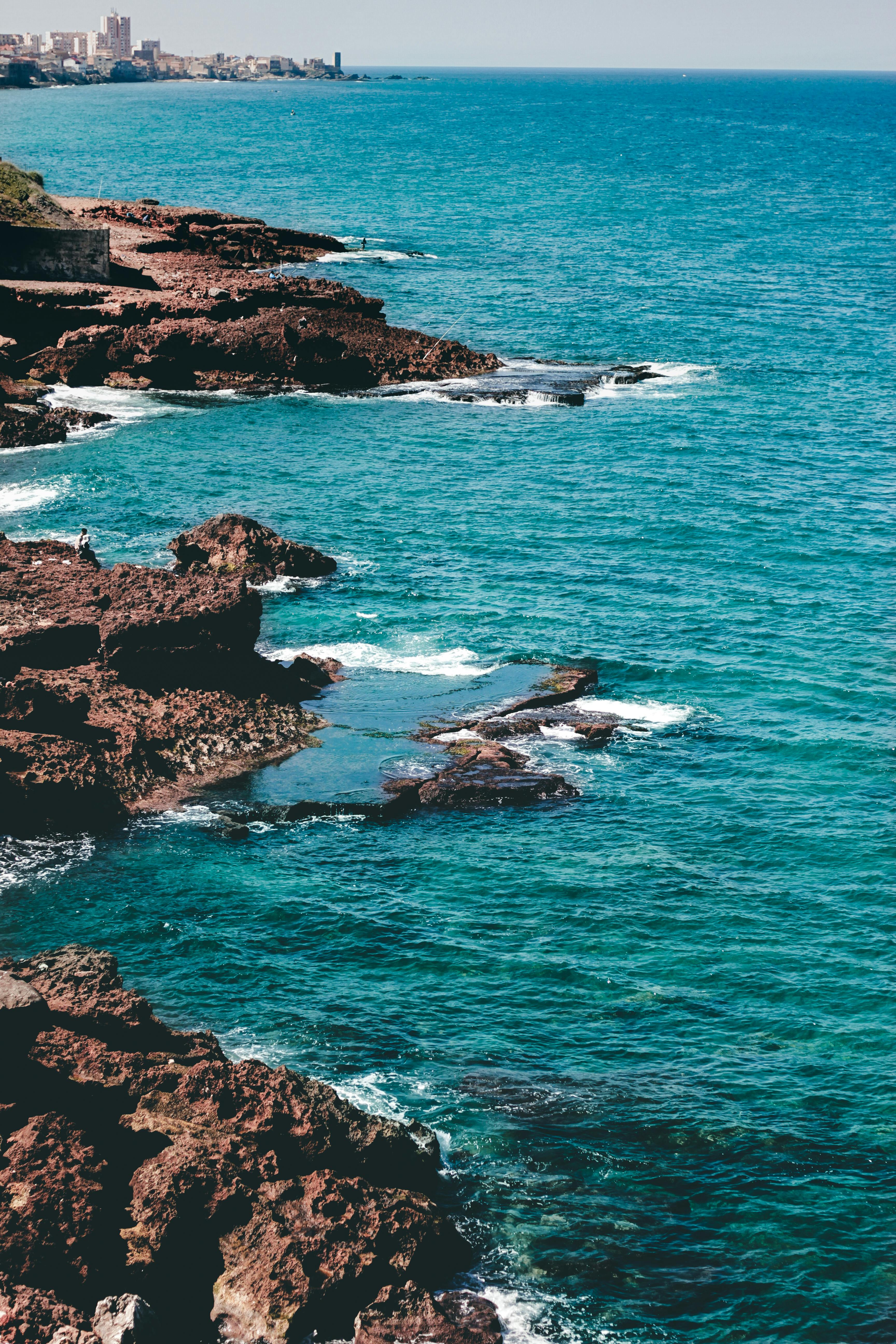A Blue Sea Beside a Rocky Shore · Free Stock Photo