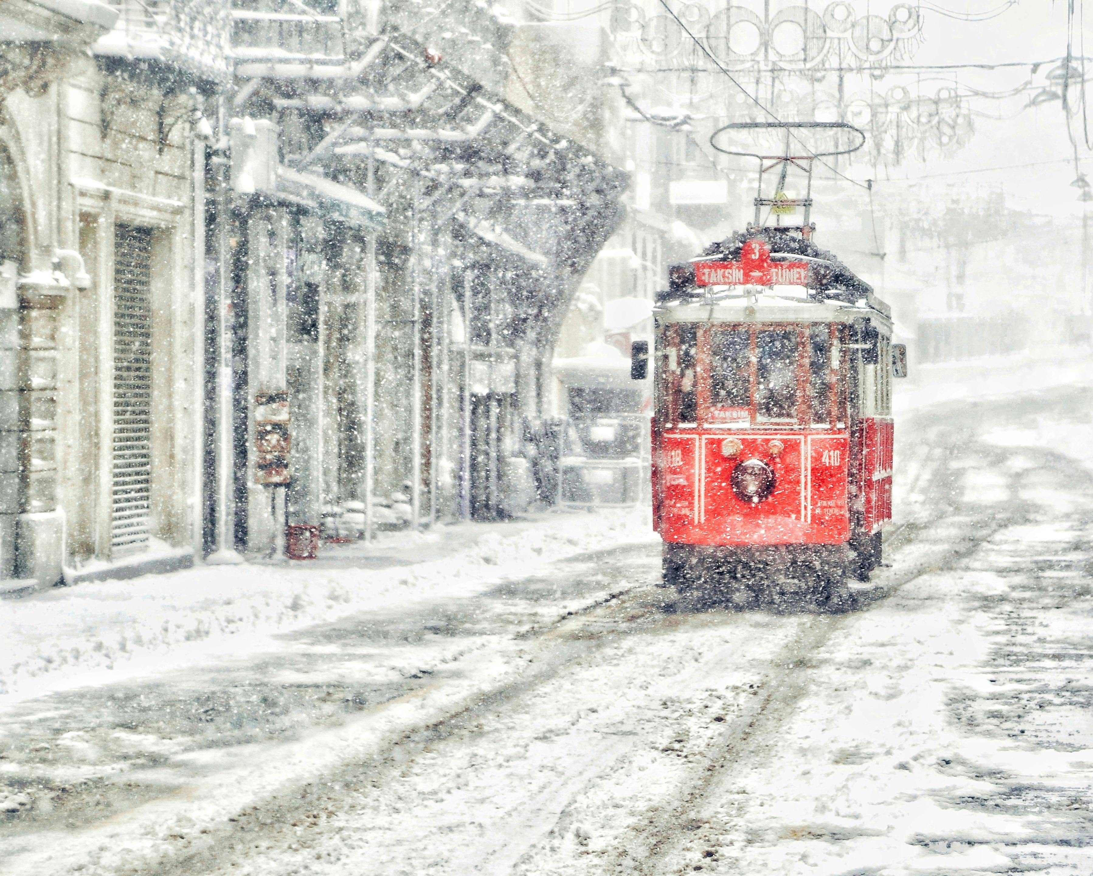 Red and White Tram on Road while Snowing · Free Stock Photo