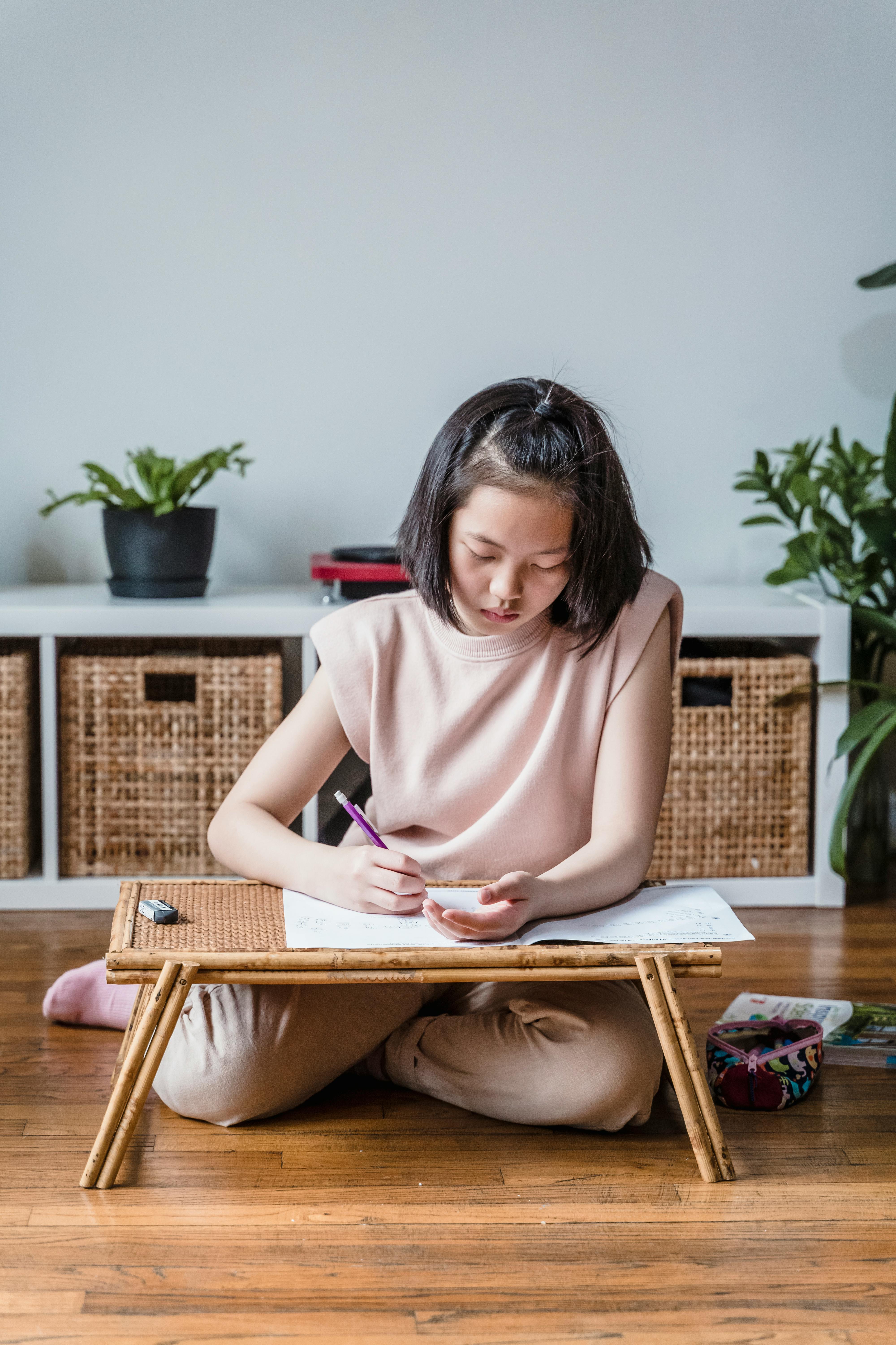 A Girl Sitting on the Wooden Floor while Studying · Free Stock Photo