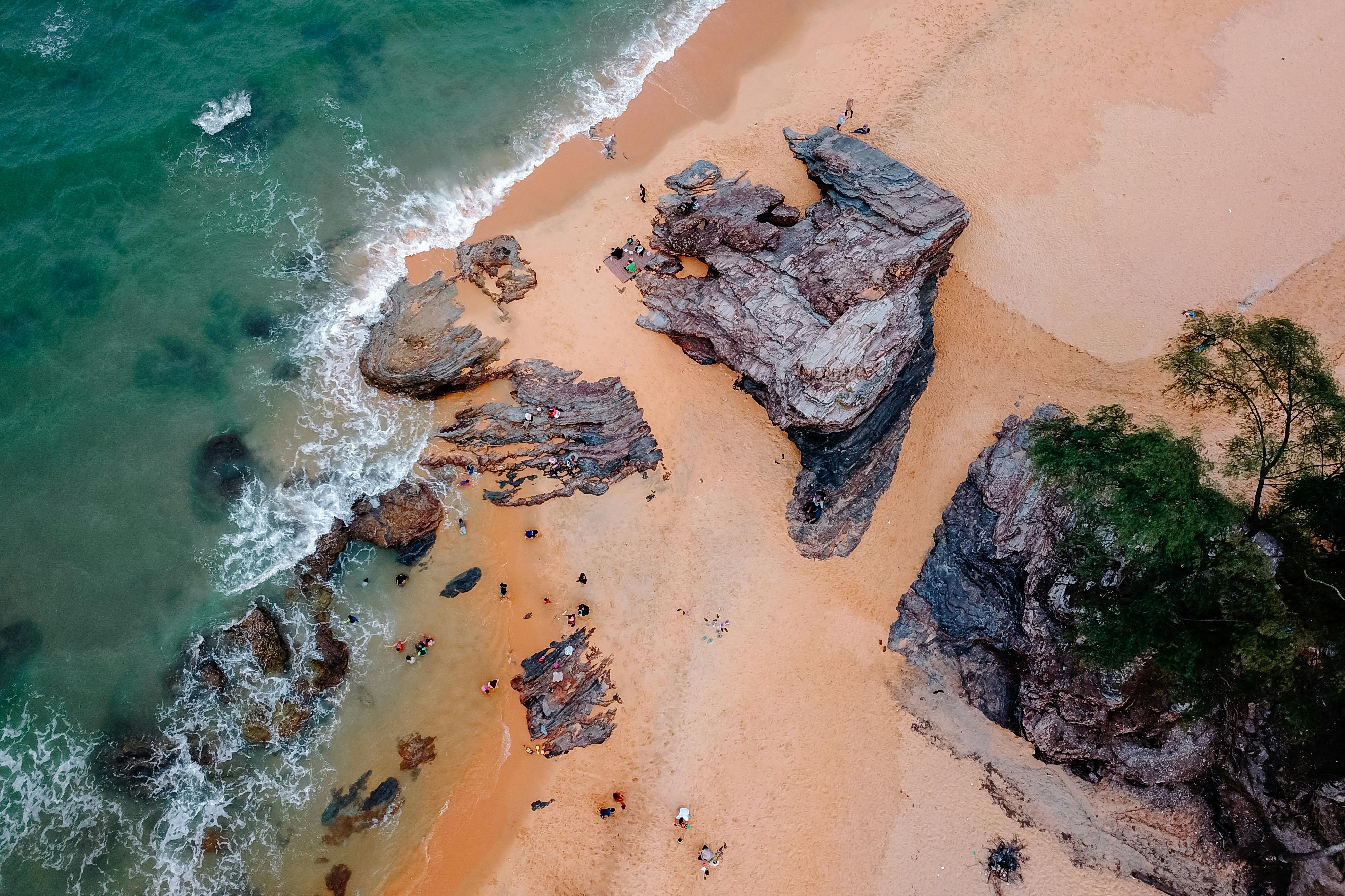 Rocky cliffs on sandy seashore on sunny day · Free Stock Photo