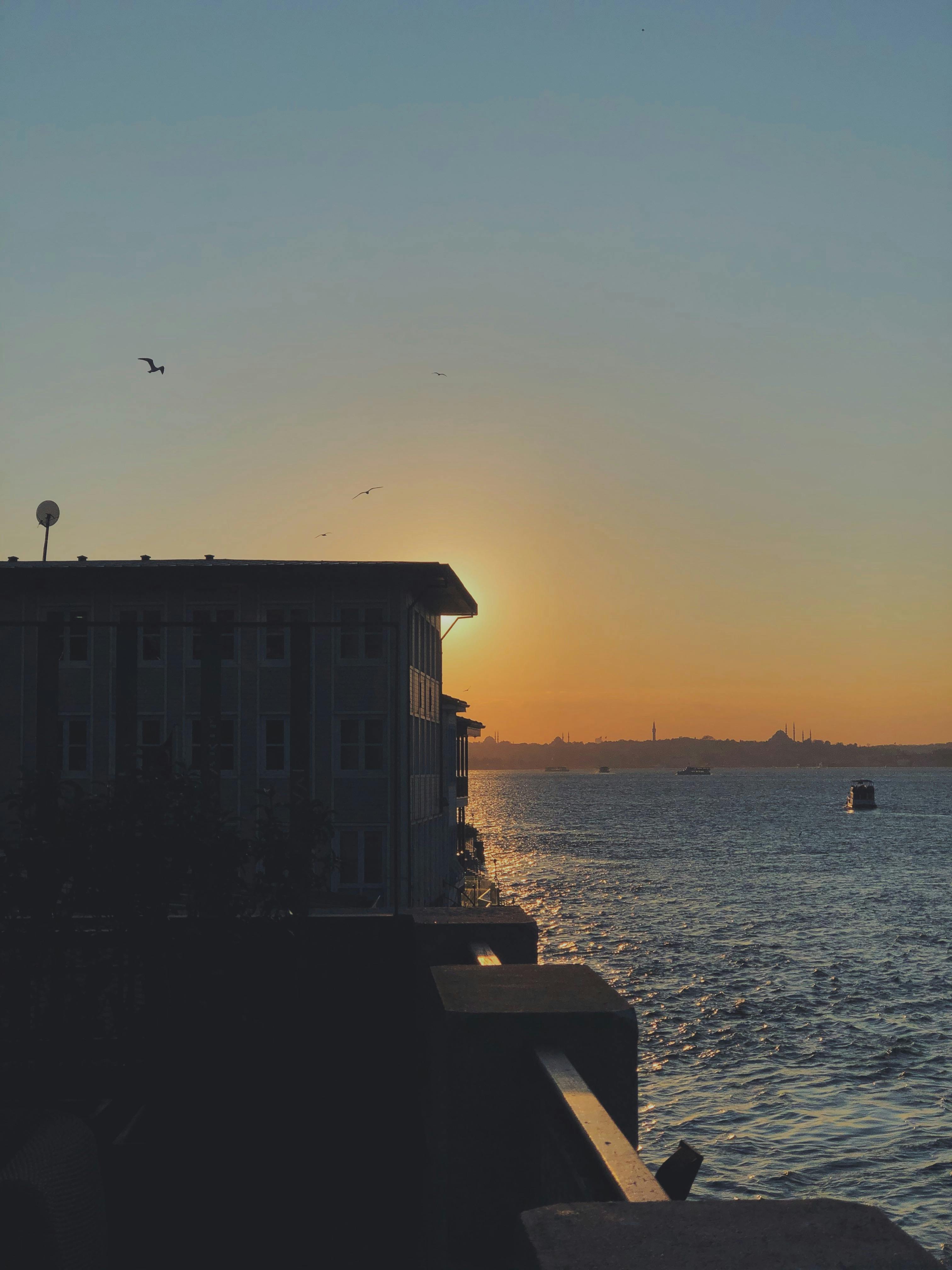 Man Standing on Roof of Building at Sunrise · Free Stock Photo
