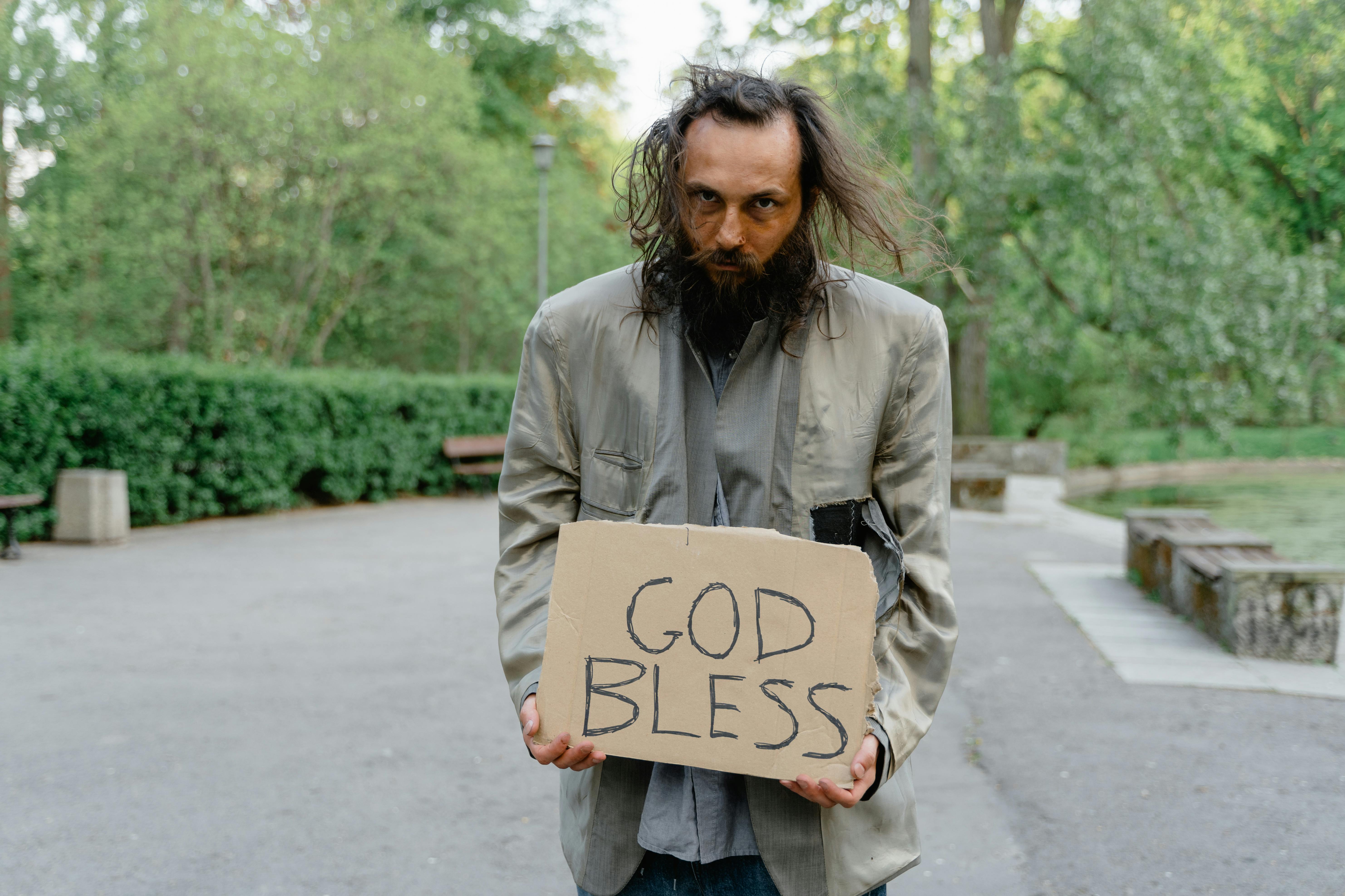 A Homeless Man Holding a Sign · Free Stock Photo
