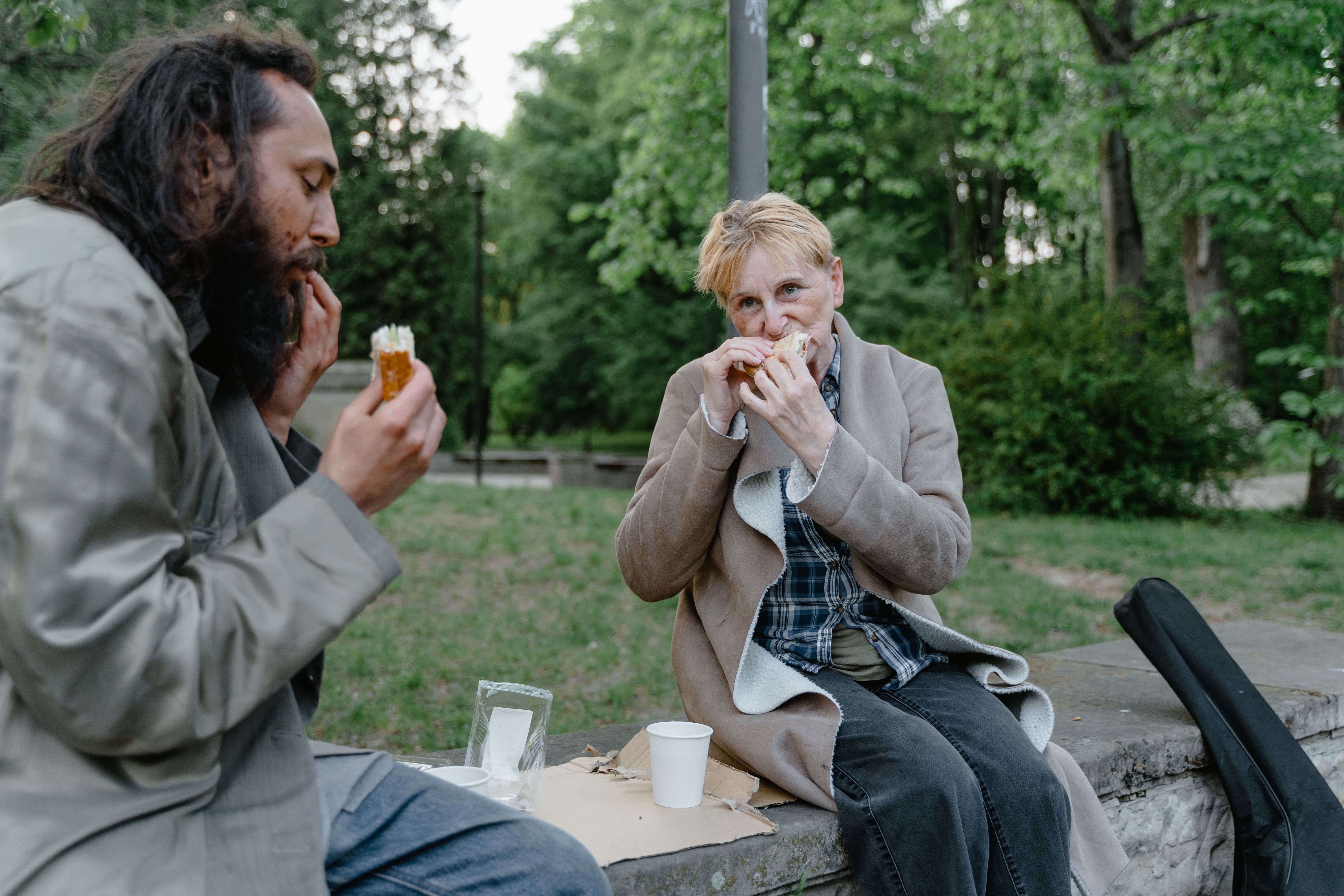 Man and Woman Sitting on a Concrete Surface Eating Sandwich · Free ...
