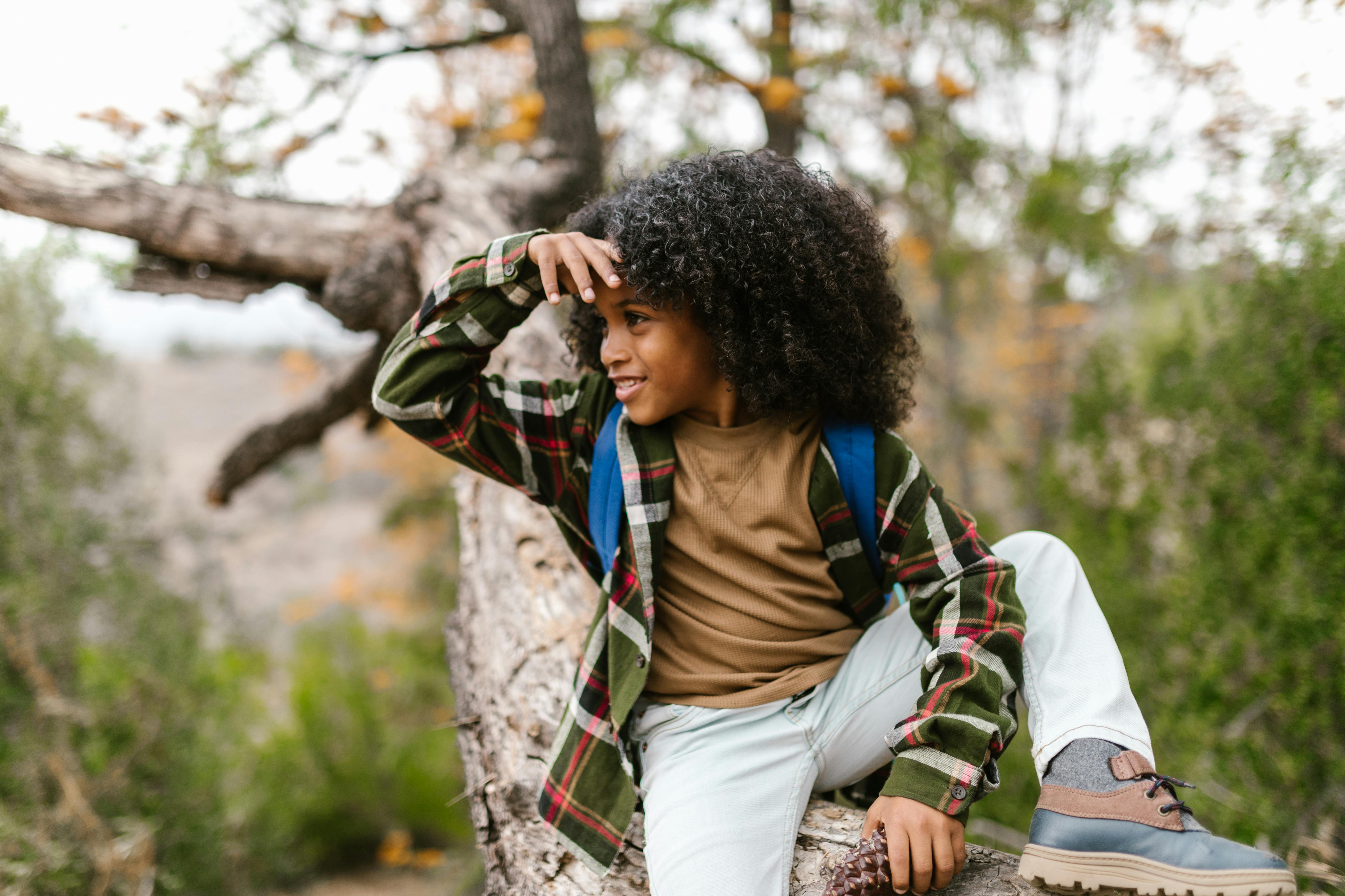 A Girl Sitting on a Tree Root Looking at a Compass · Free Stock Photo