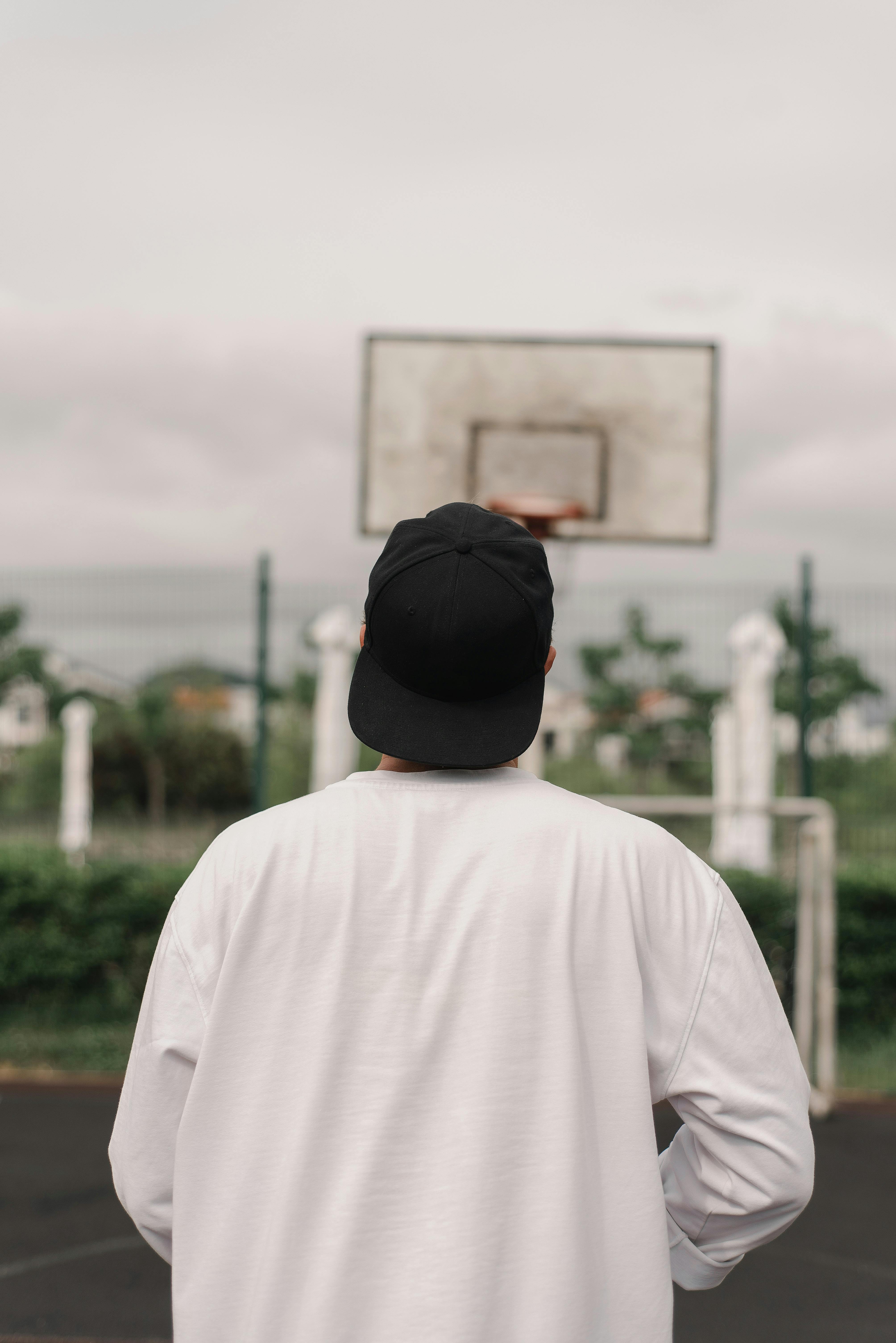 A Man in White Sweater and Black Cap in a Basketball Court · Free Stock ...