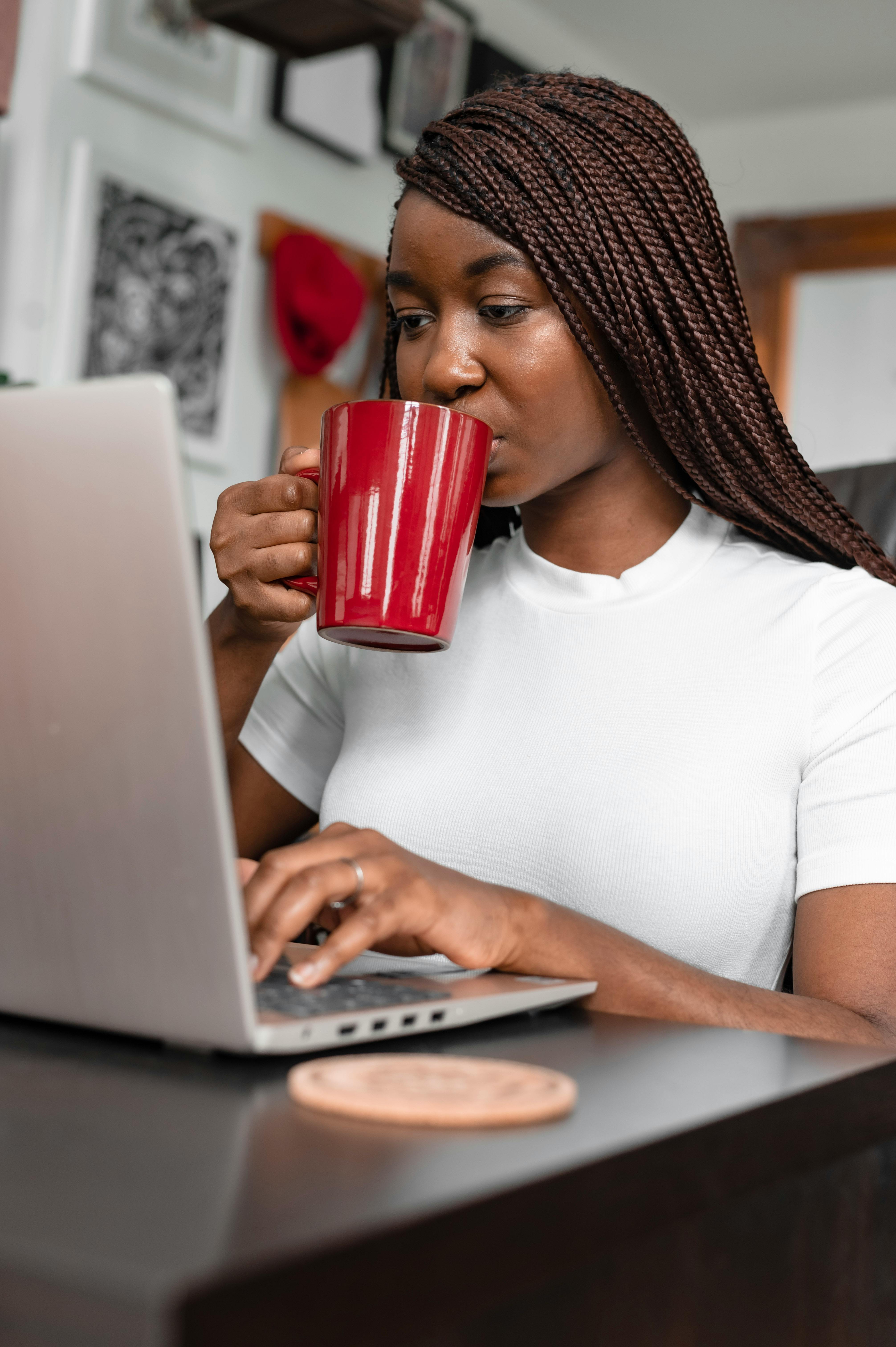 A Woman Drinking Coffee while using Laptop · Free Stock Photo