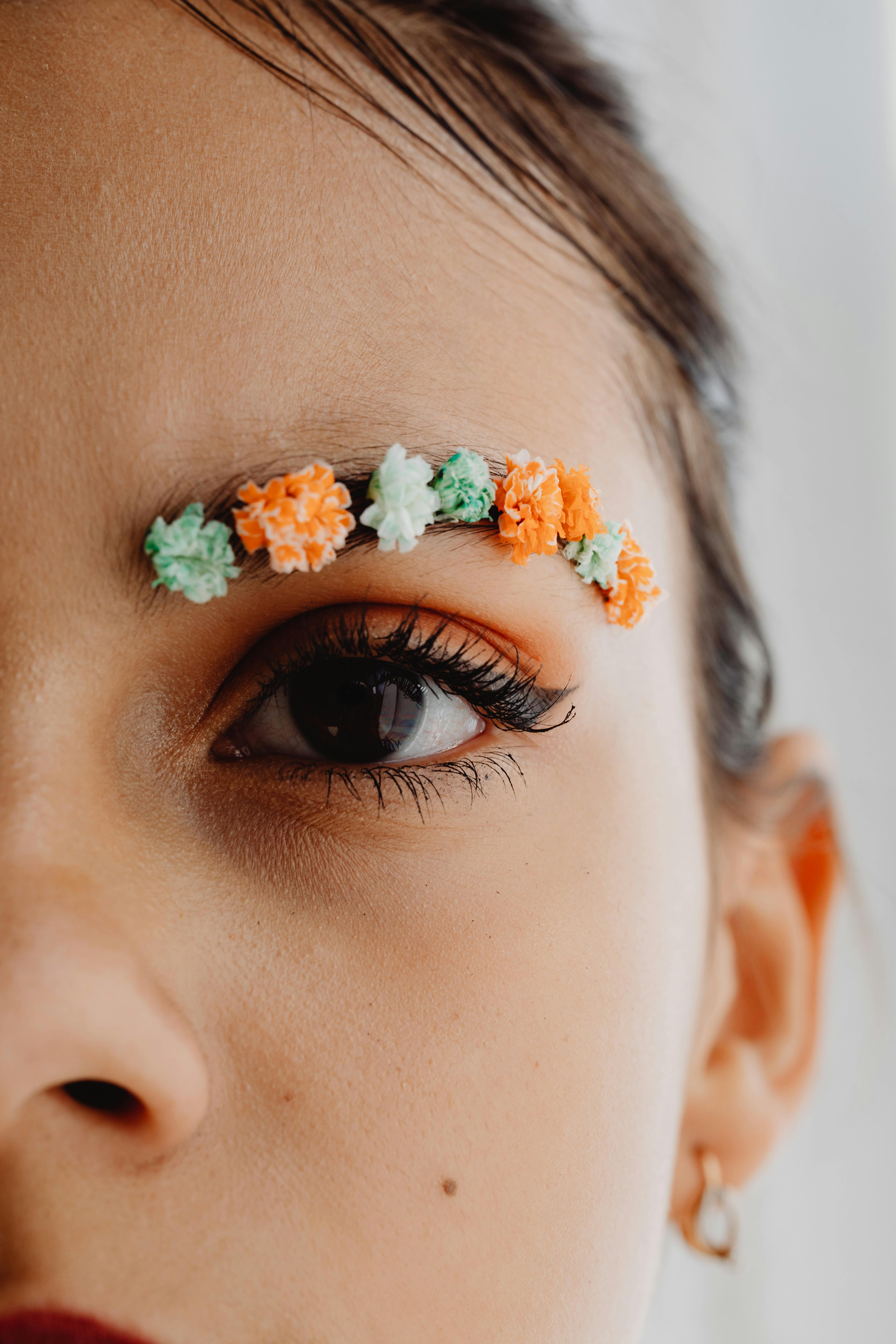 A Close-Up Shot of Woman's Eyebrow with Small Flowers · Free Stock Photo