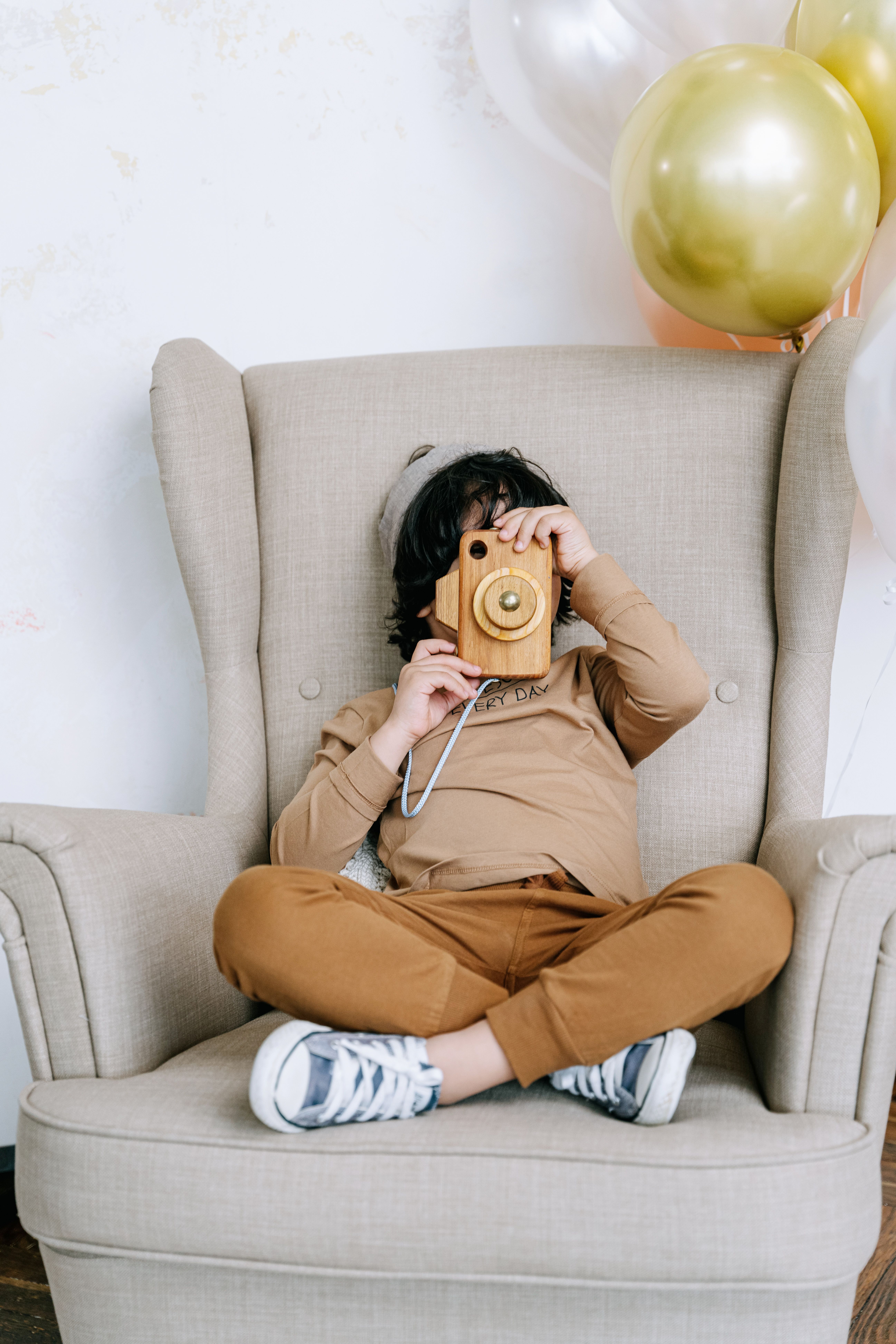 Boy Sitting on Sofa Chair While Holding Toy Camera · Free Stock Photo