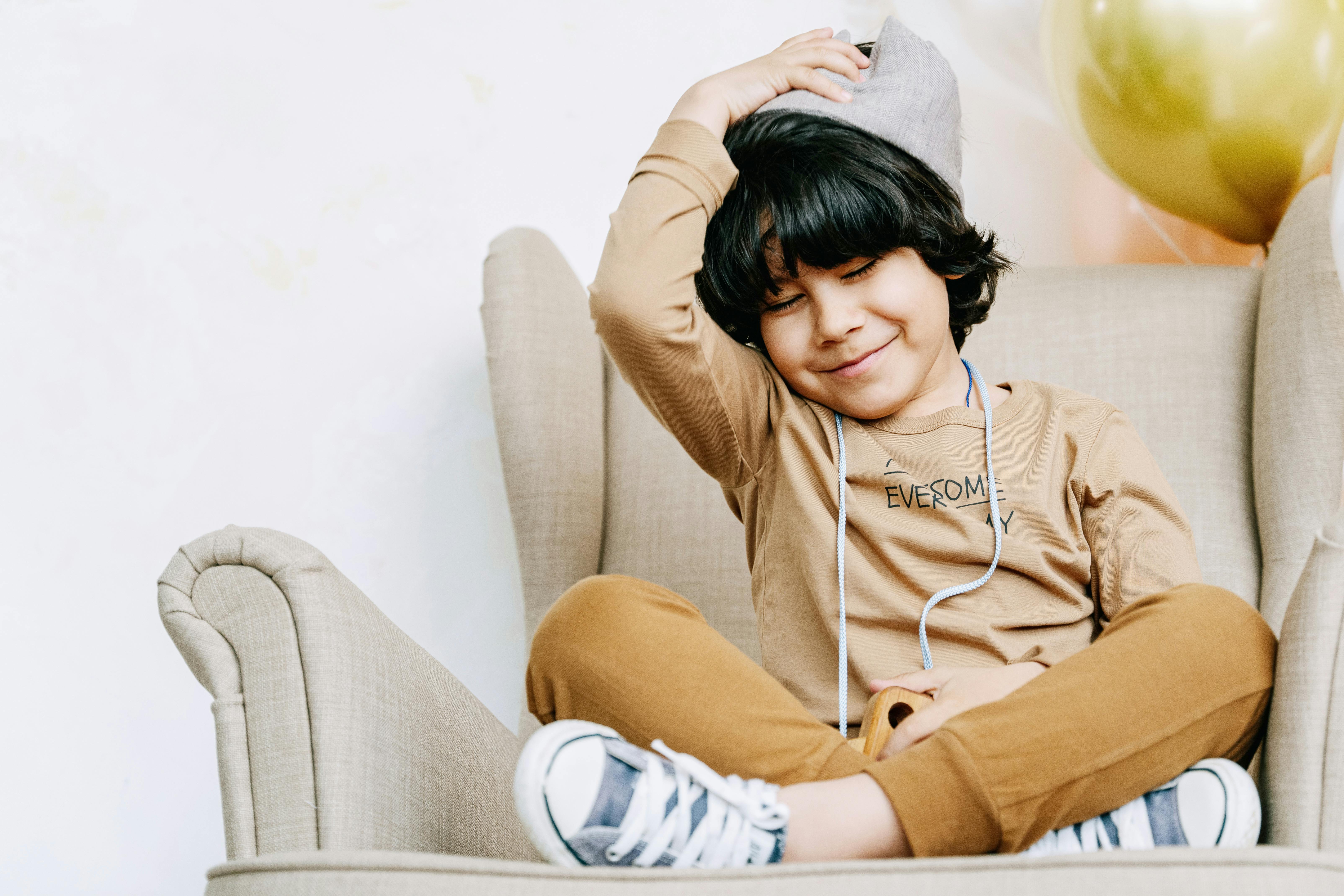 Boy in Brown Top Sitting on Sofa Chair · Free Stock Photo