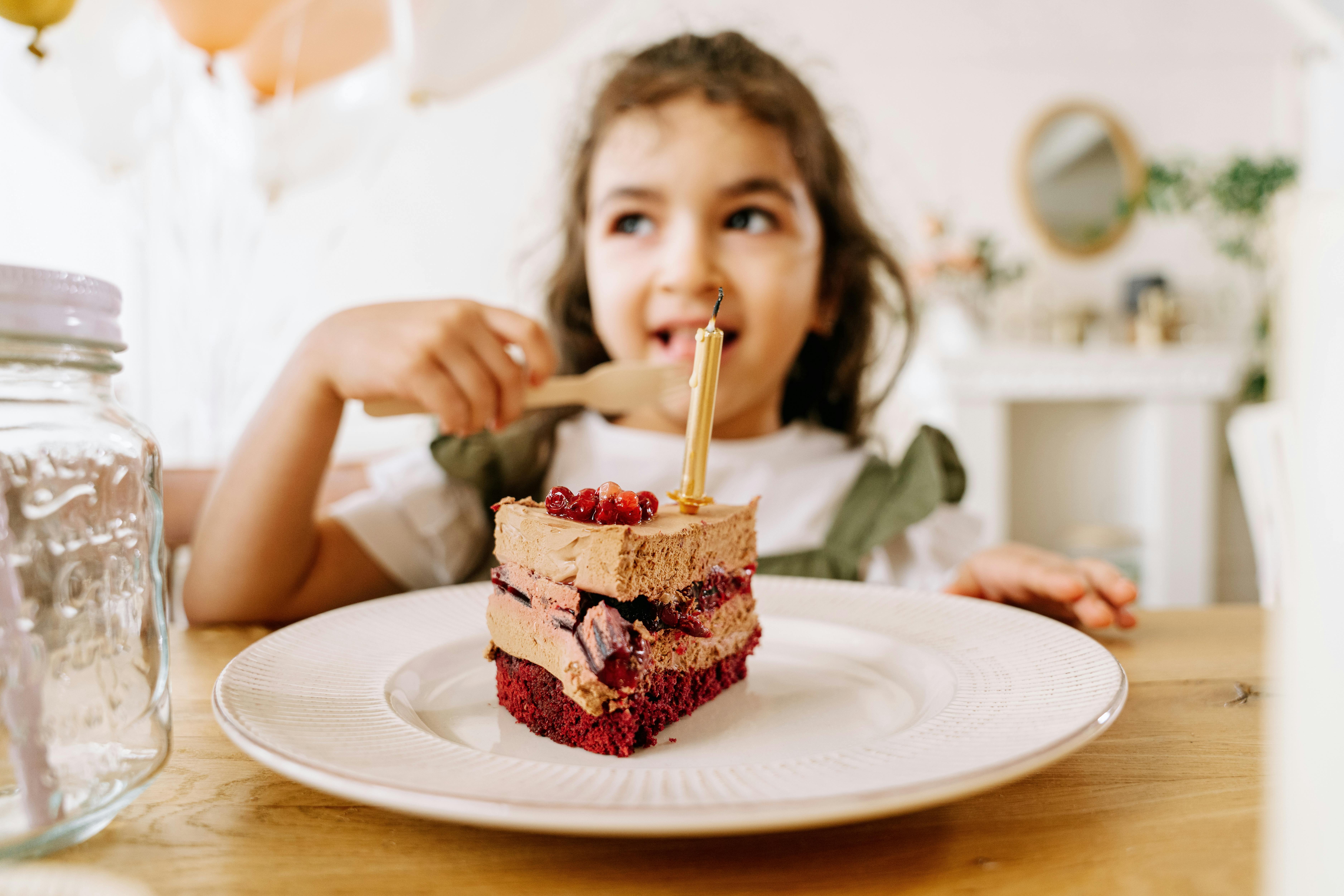 A Girl Eating a Cake with a Candle · Free Stock Photo